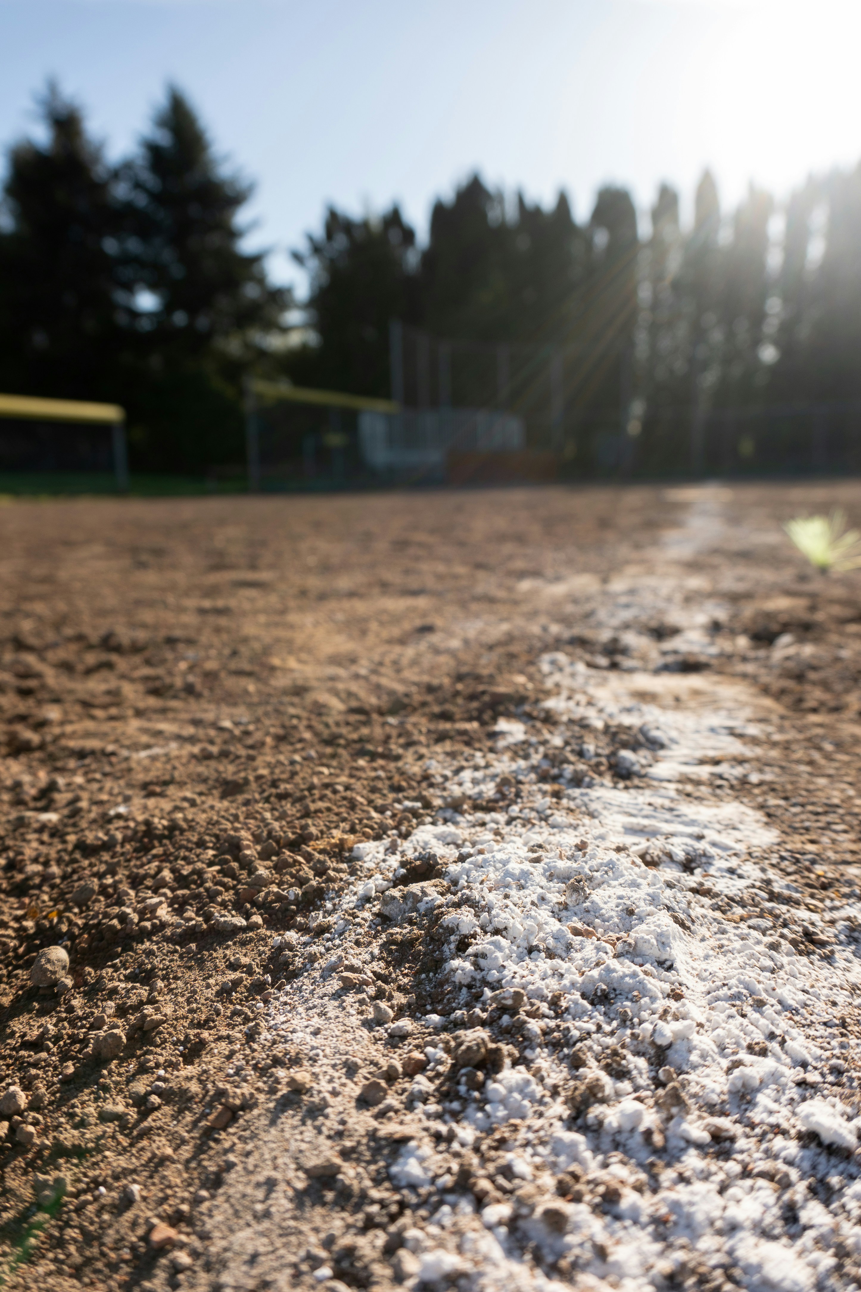 A baseball field with a dirt field and trees in the background photo ...