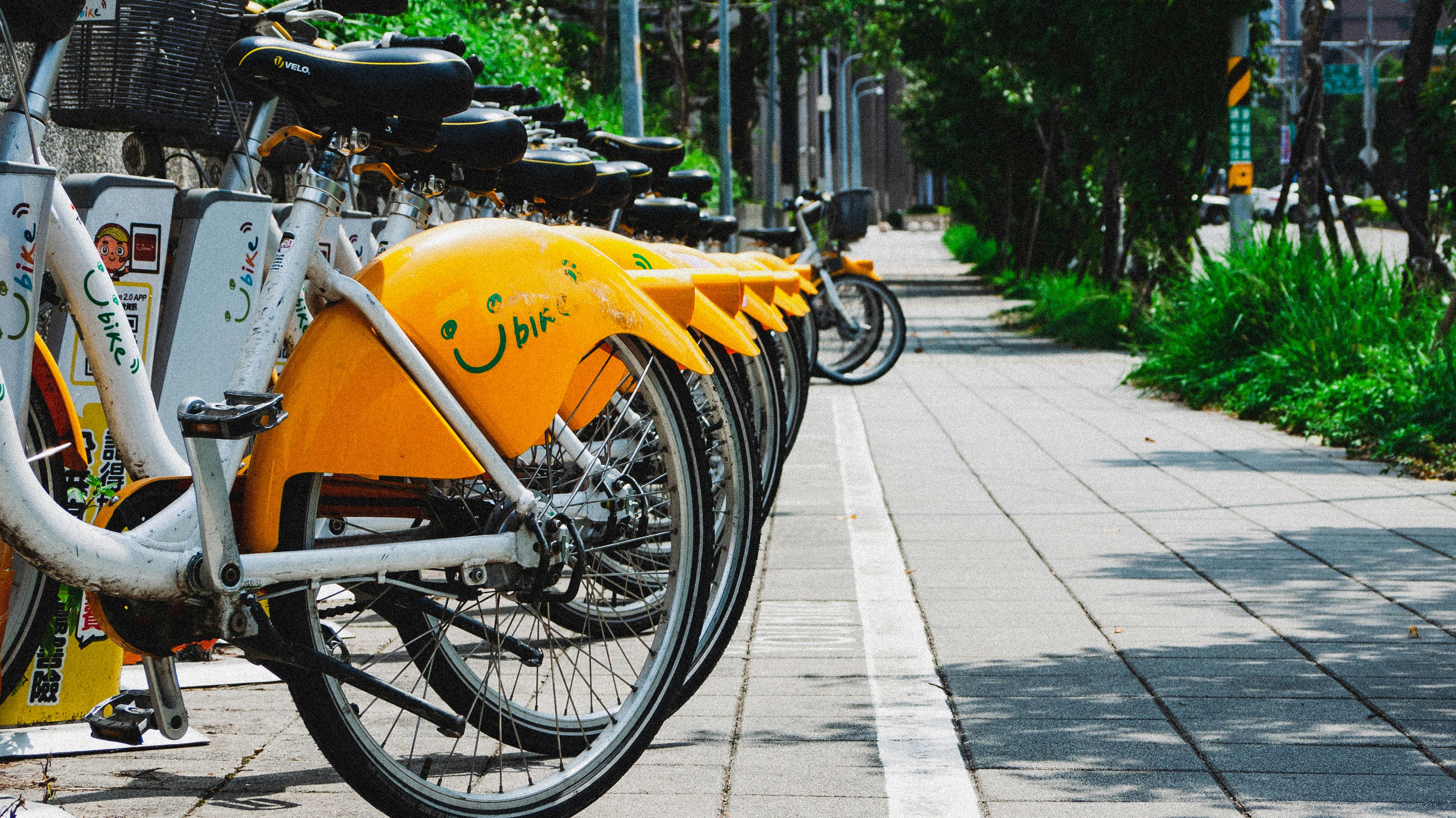 A row of bikes parked next to each other on a sidewalk photo – Free ...