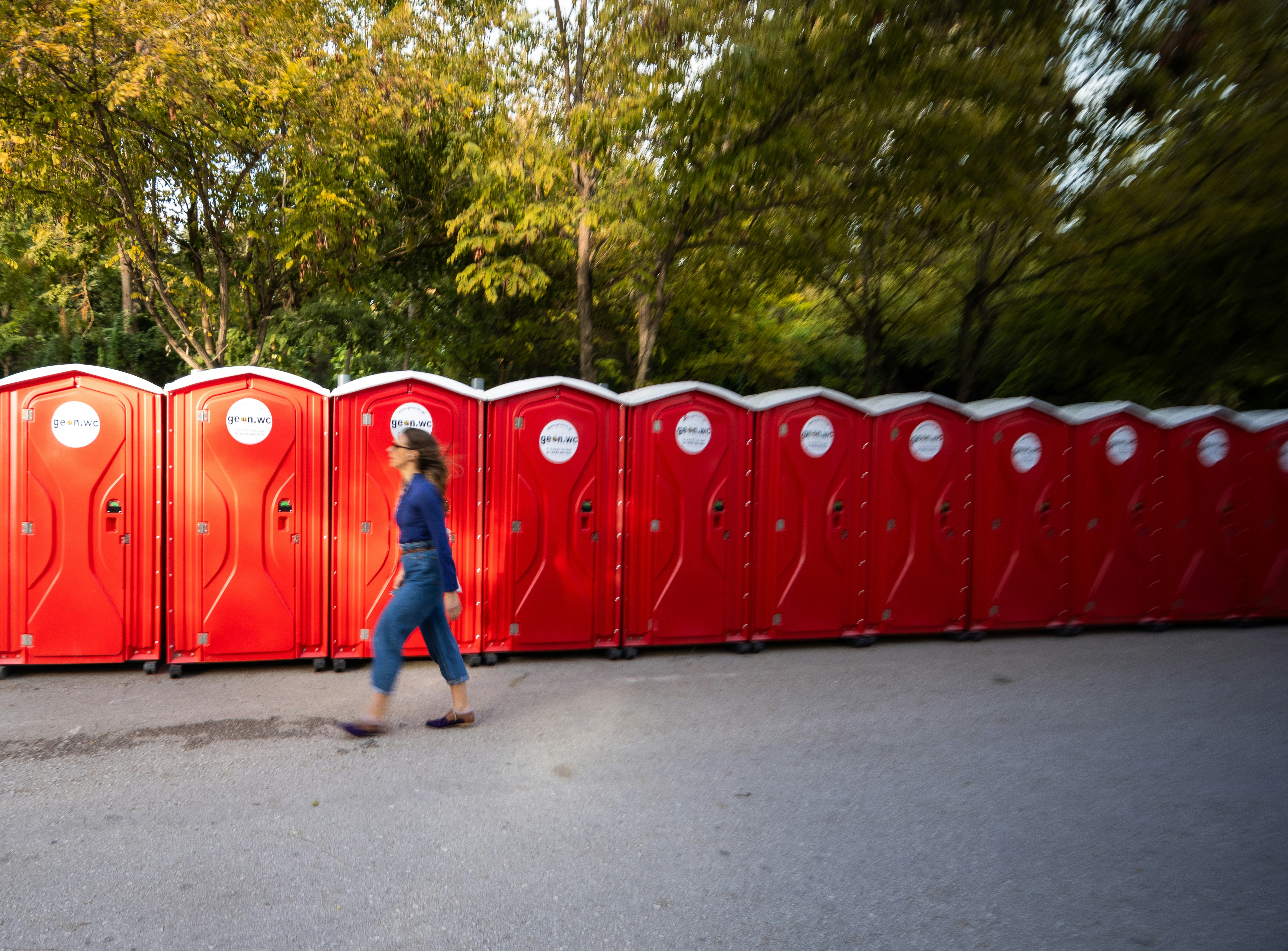 A woman walking past a row of red portable toilets photo – Free Street ...