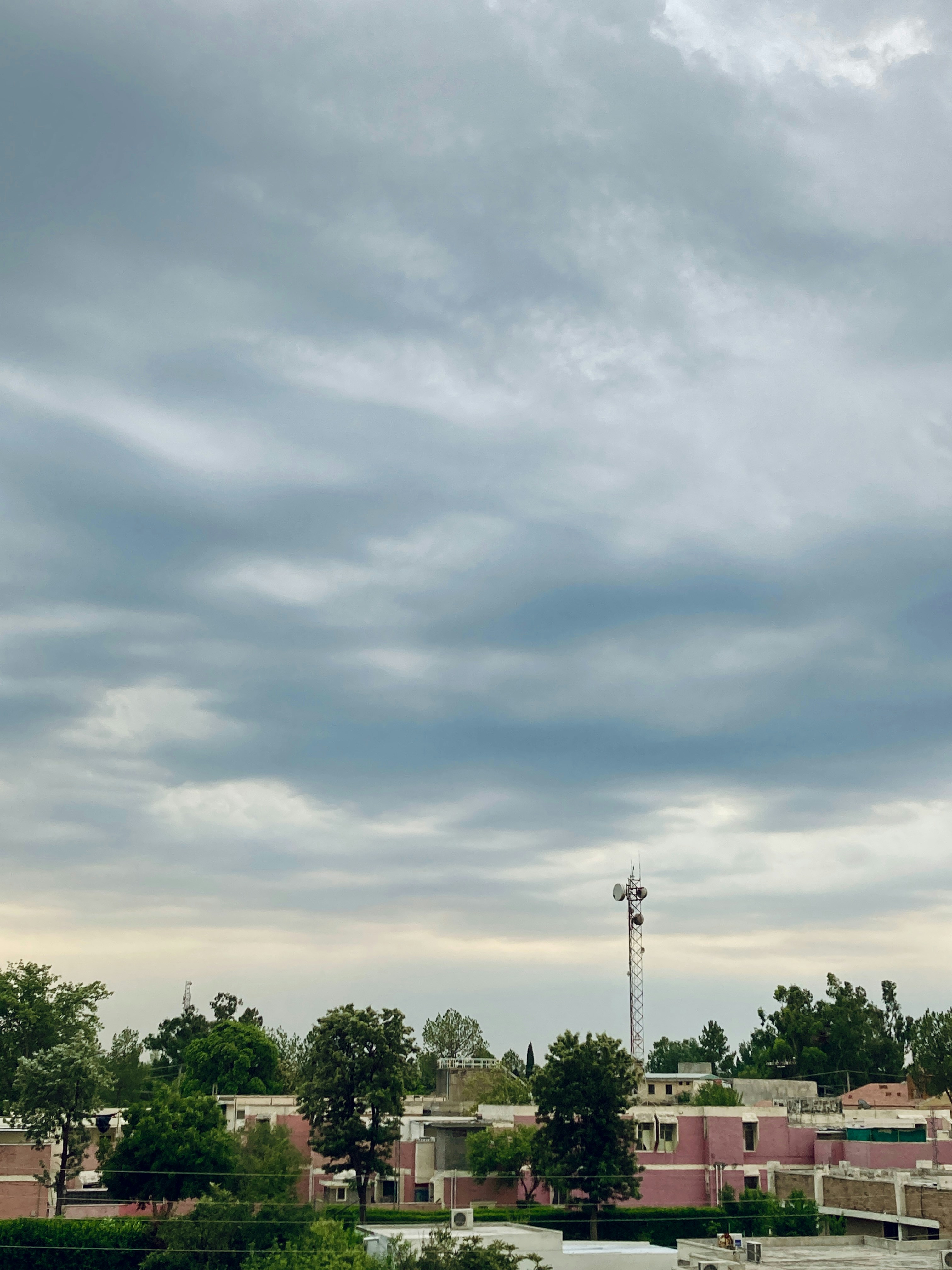 The Suburban Sentinel: A Telecom Tower Rises Beneath a Layered Cloudscape