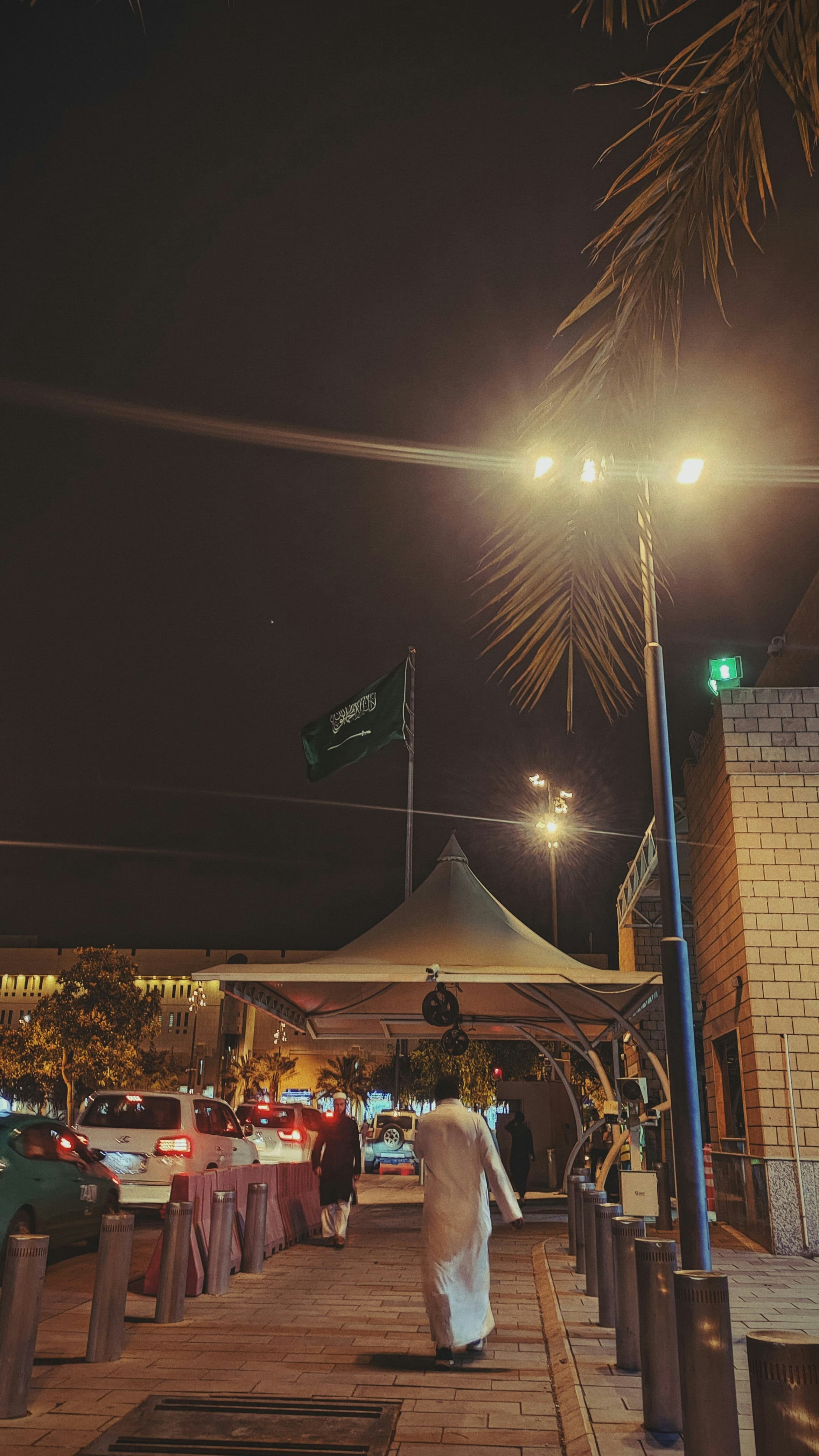 A person walking down a sidewalk at night photo – Free Riyadh saudi ...