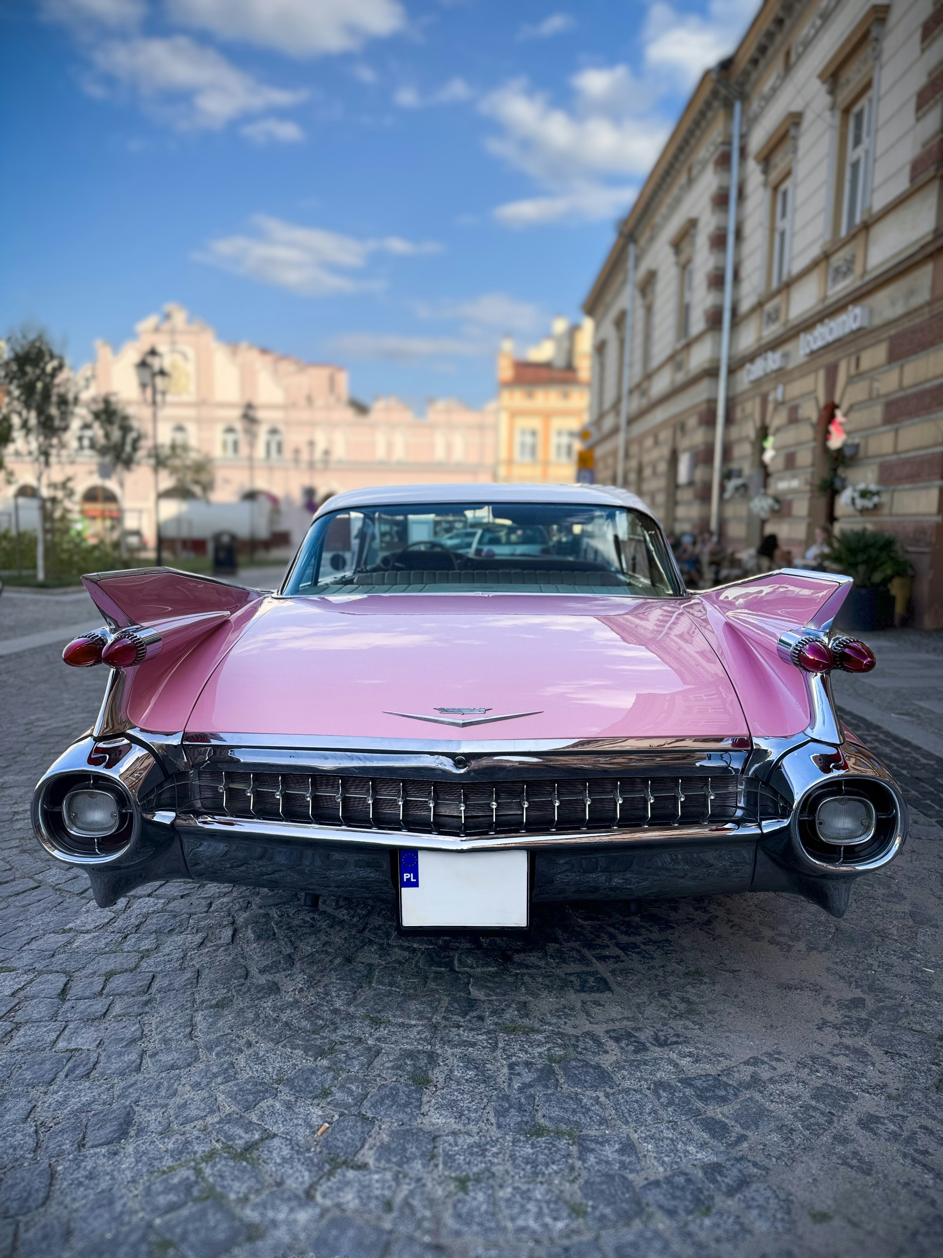 Um carro clássico cor-de-rosa estacionado em uma rua de paralelepípedos ...
