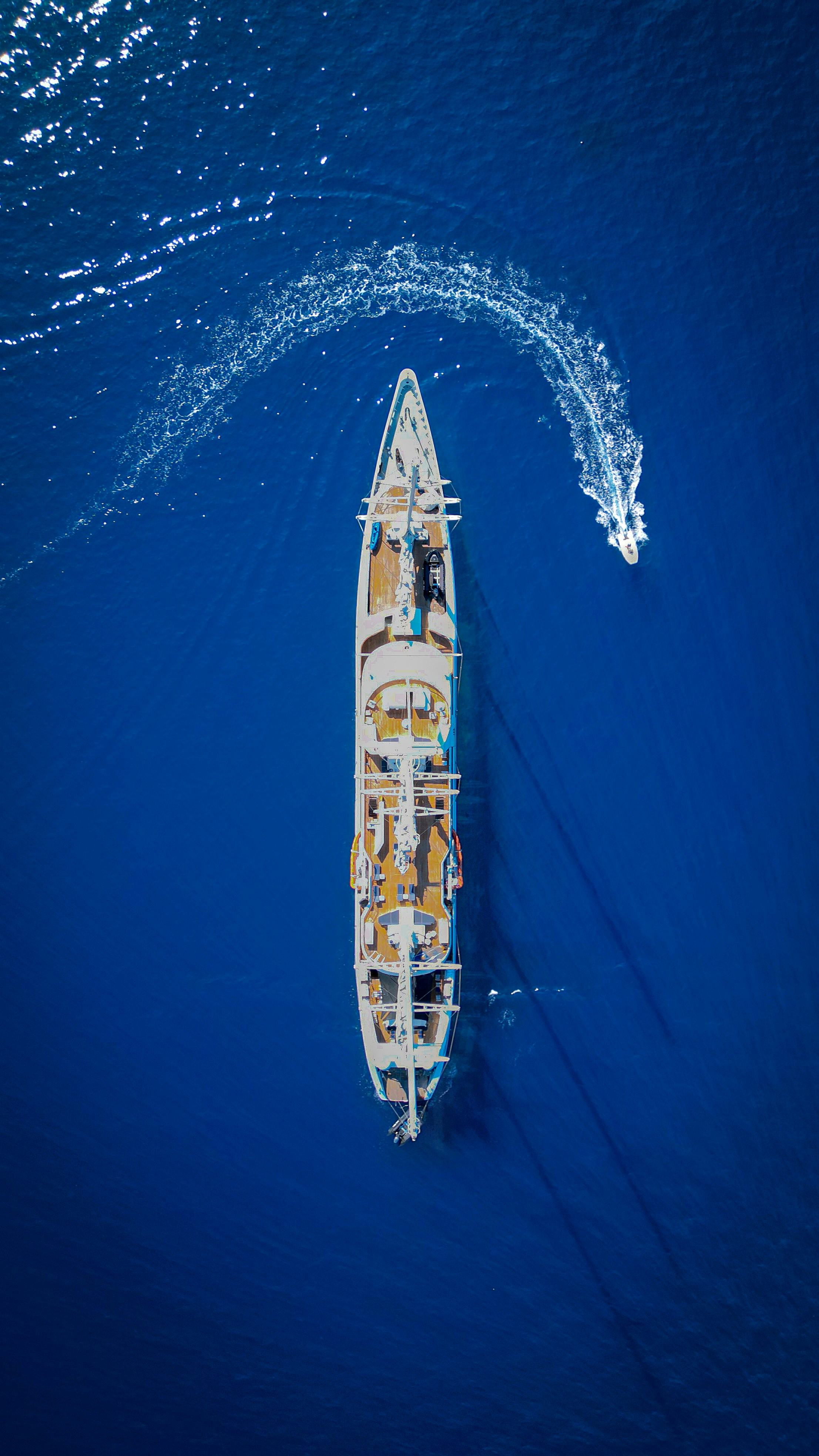 Vertical Voyage: Aerial Portrait of a Classic Wooden Yacht in Cerulean Seas