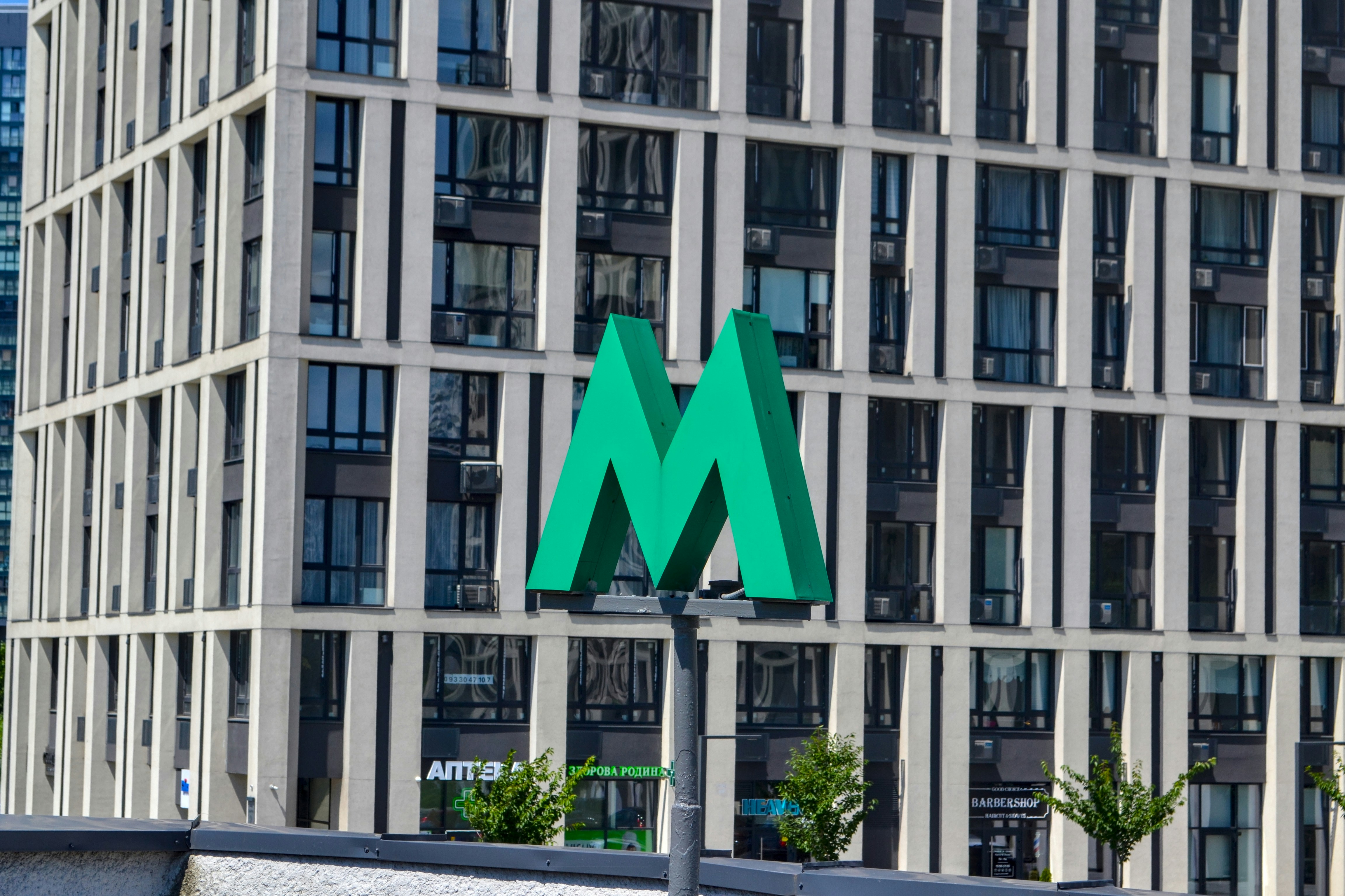A green m sign in front of a tall building photo – Free Building Image ...