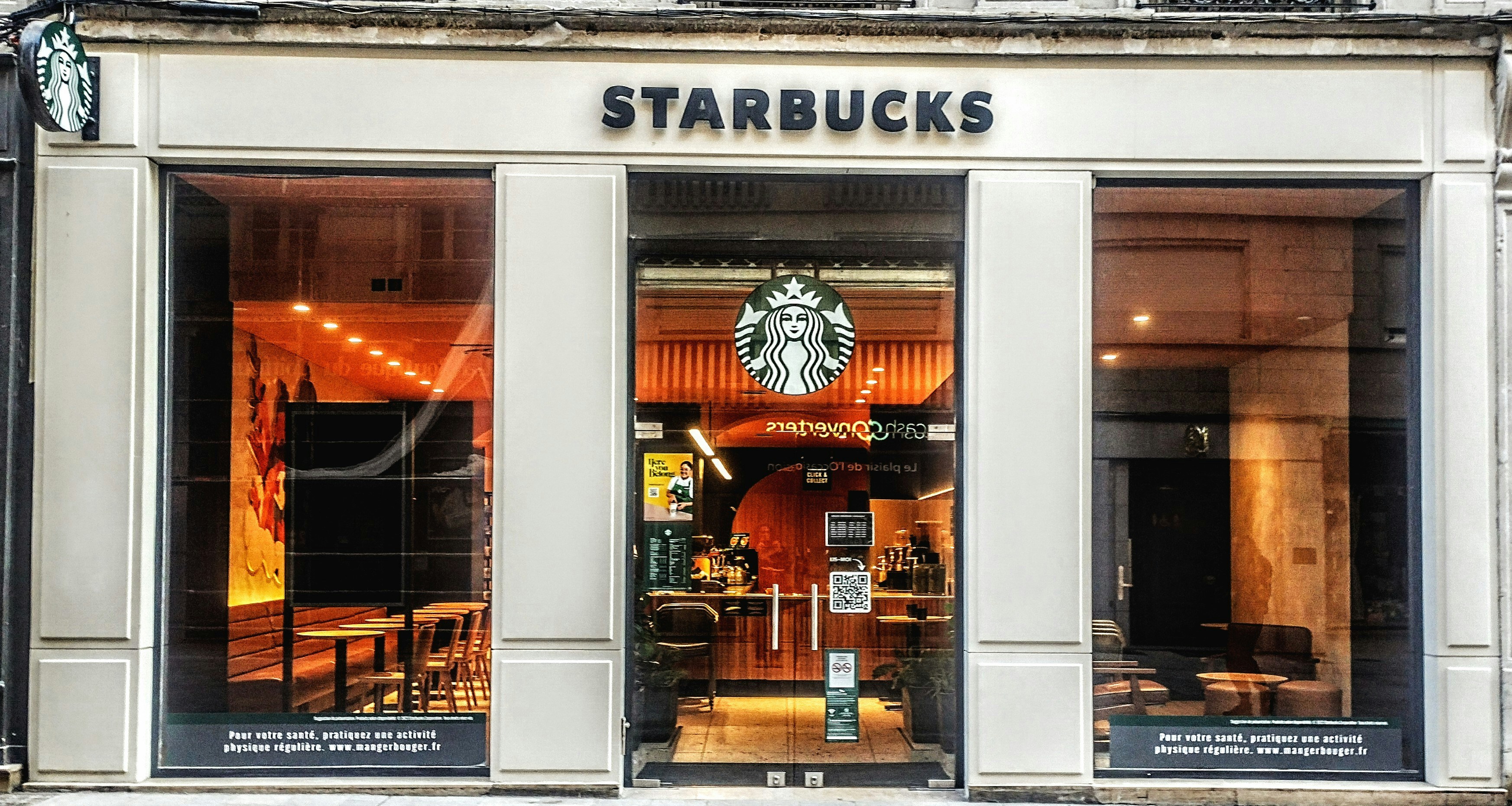 A starbucks store front with a clock in the window photo – Free Human ...