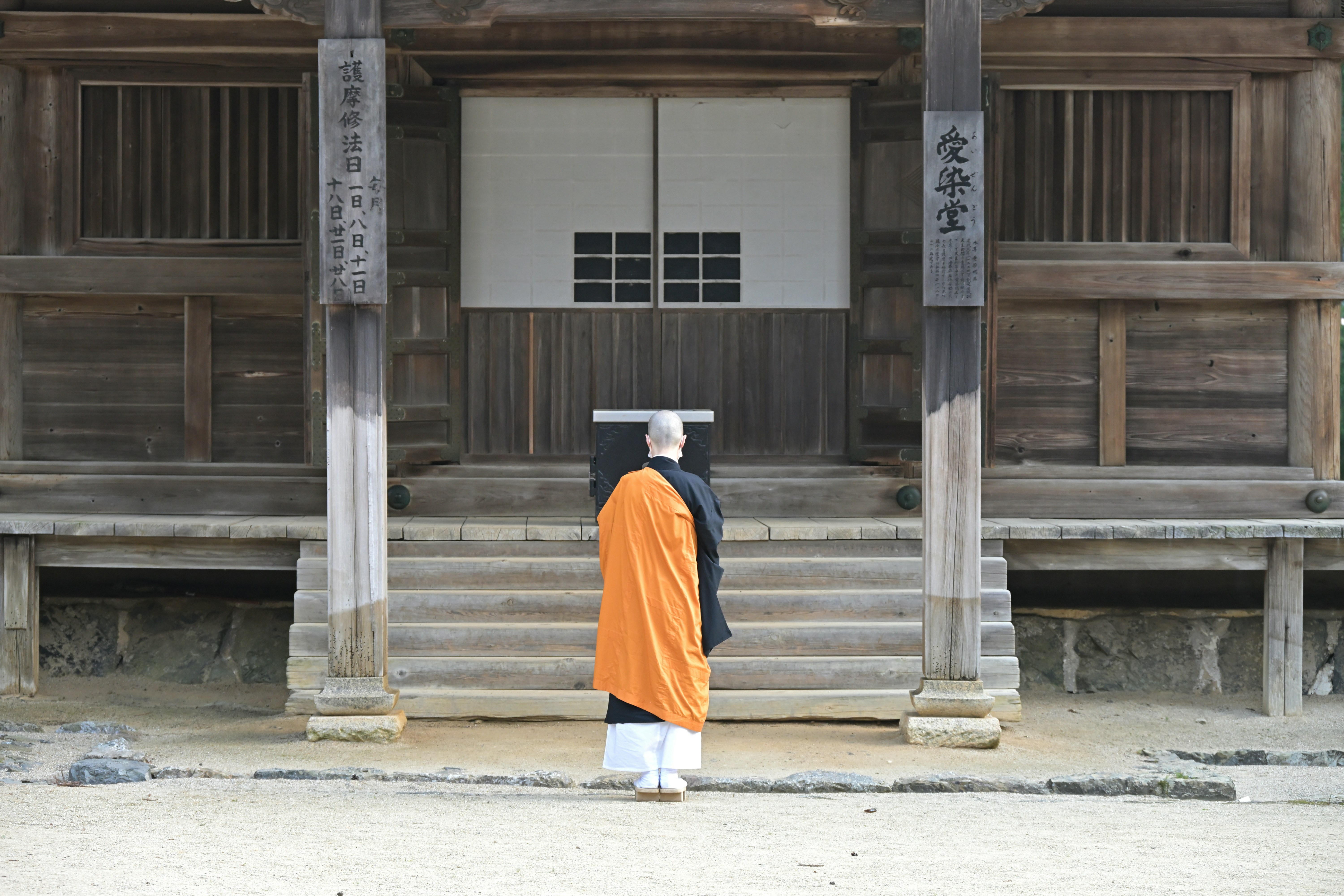 A person in an orange robe standing in front of a building photo – Free ...