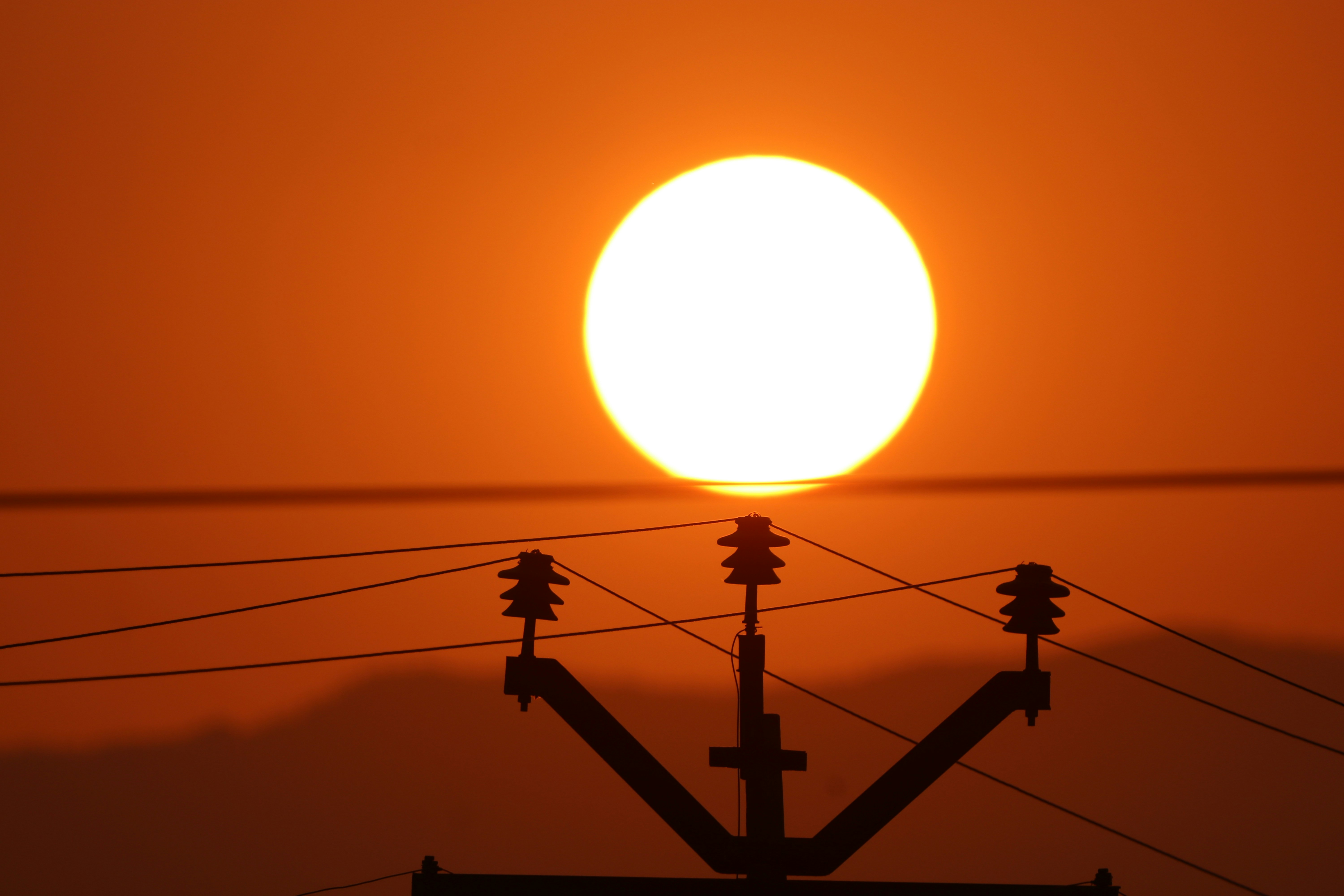 Crimson Sundown Over a Silhouetted Transmission Grid