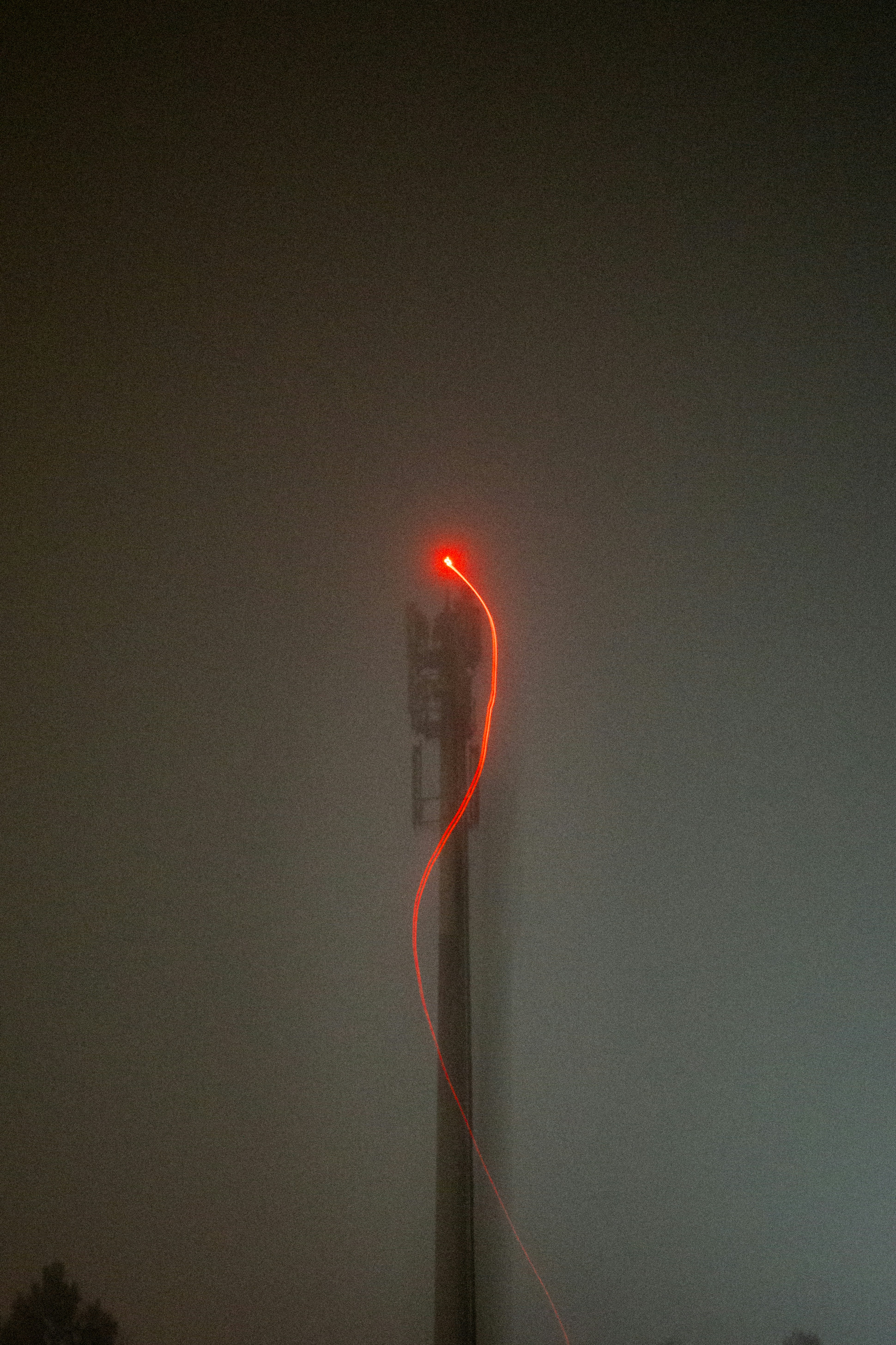 Crimson Arc Over a Fogbound Tower at Night