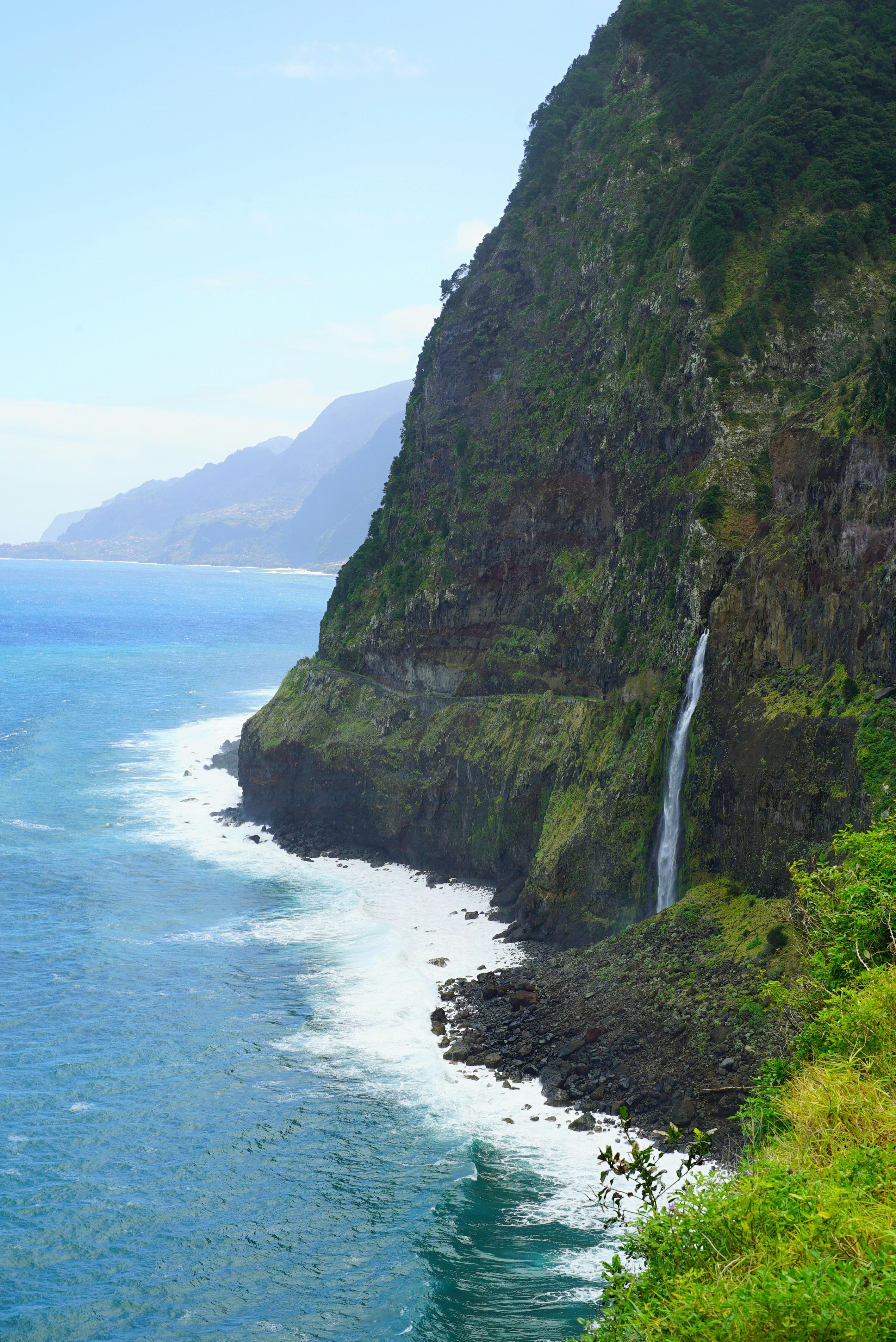 A view of a waterfall from a cliff overlooking the ocean photo – Free ...
