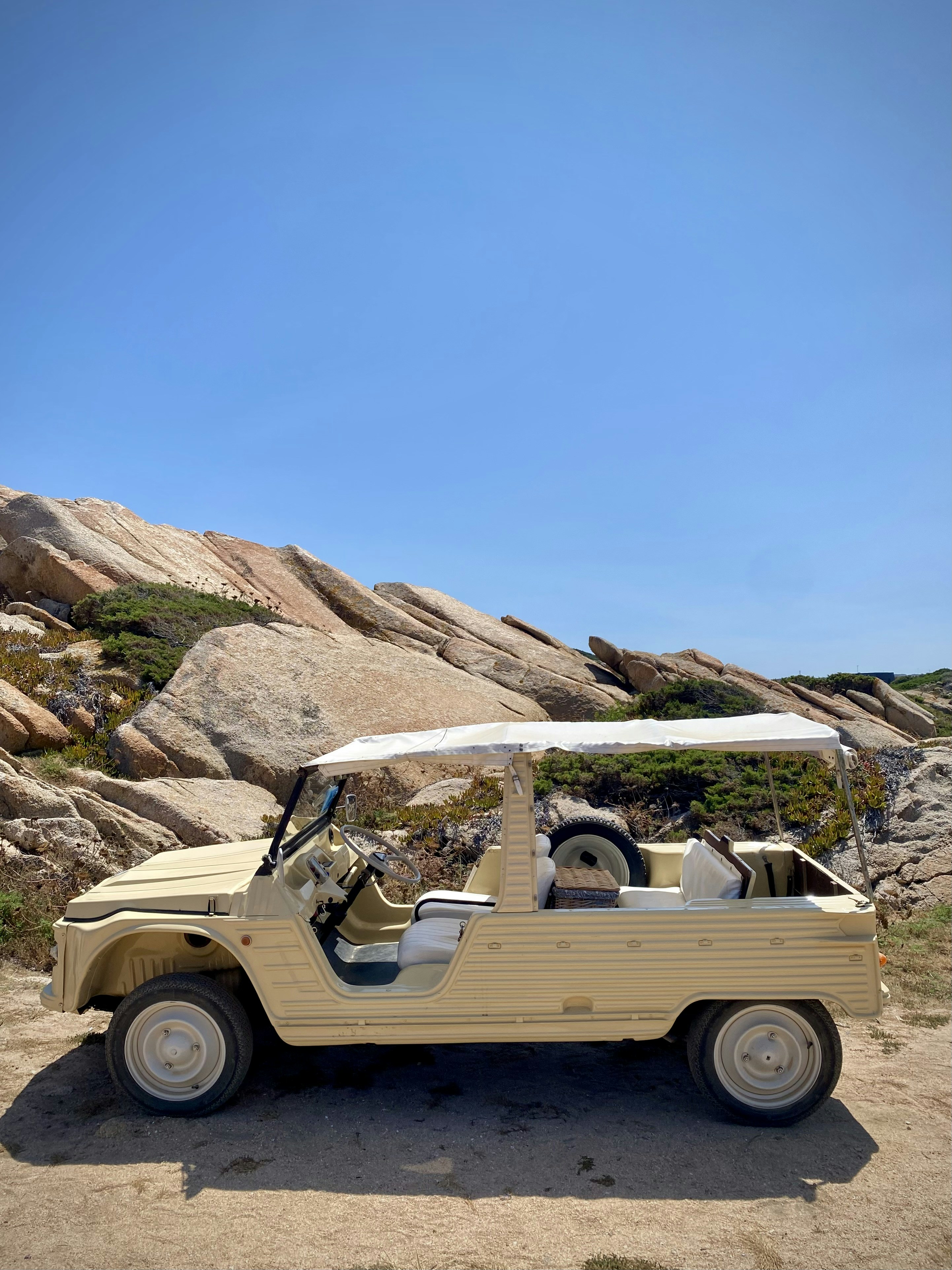 Beige Vintage Jeep Anchored Among Rugged Granite and Sea Air