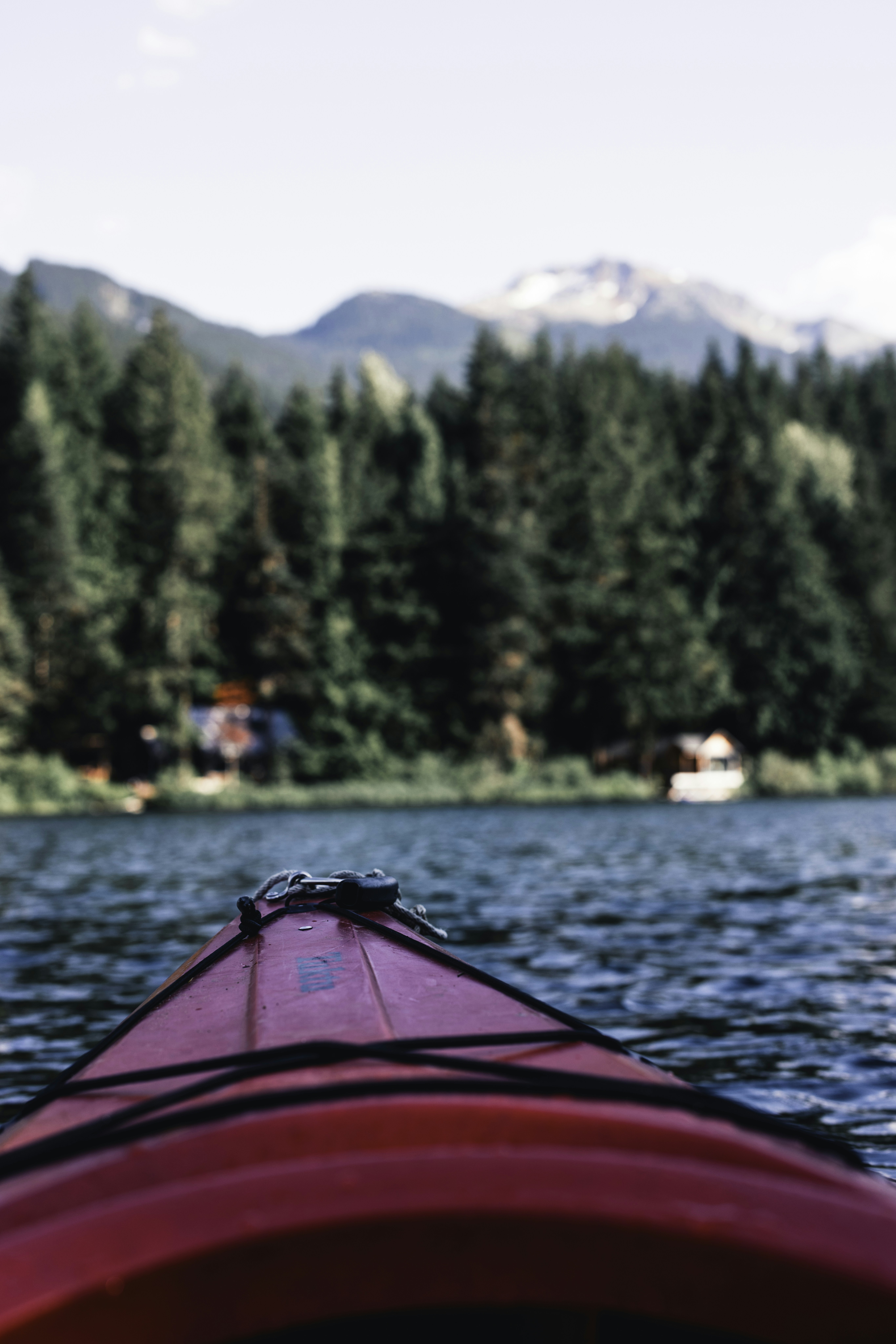 A red kayak sitting on top of a lake next to a forest photo – Free ...