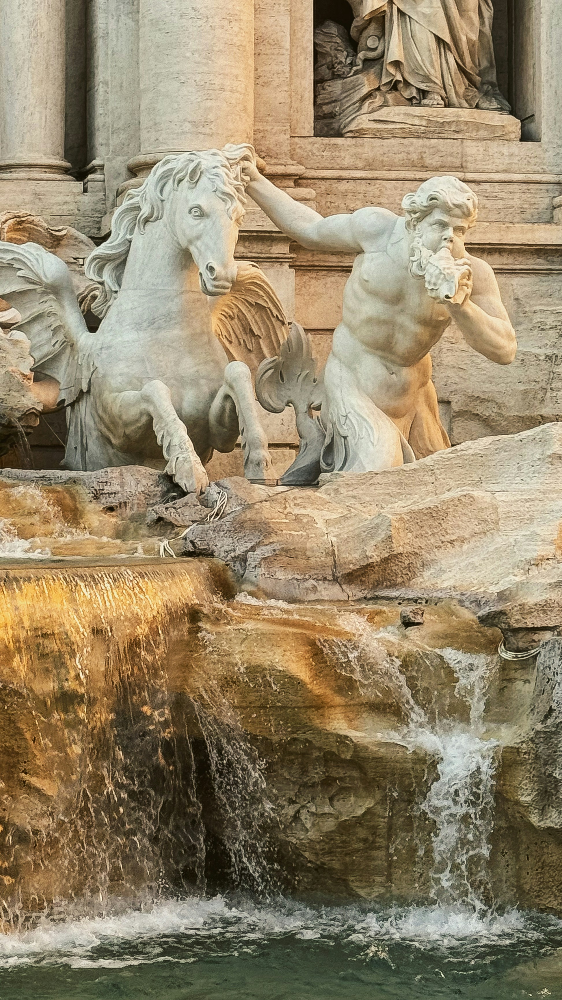 Intricate statues of a man and a horse with flowing water at a historic fountain.