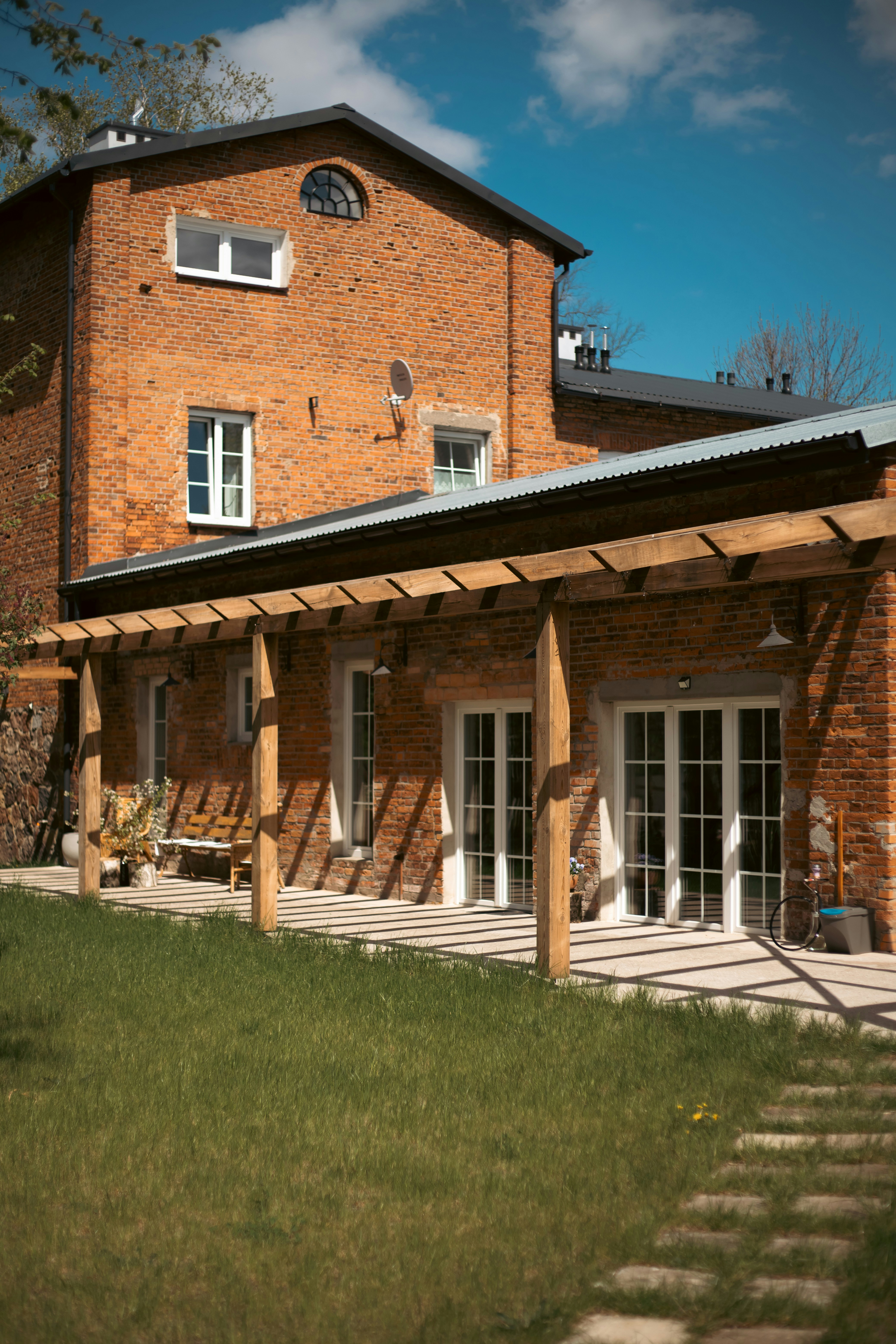 Brick House Terrace: Sunlit Patio Beneath Wooden Pergola