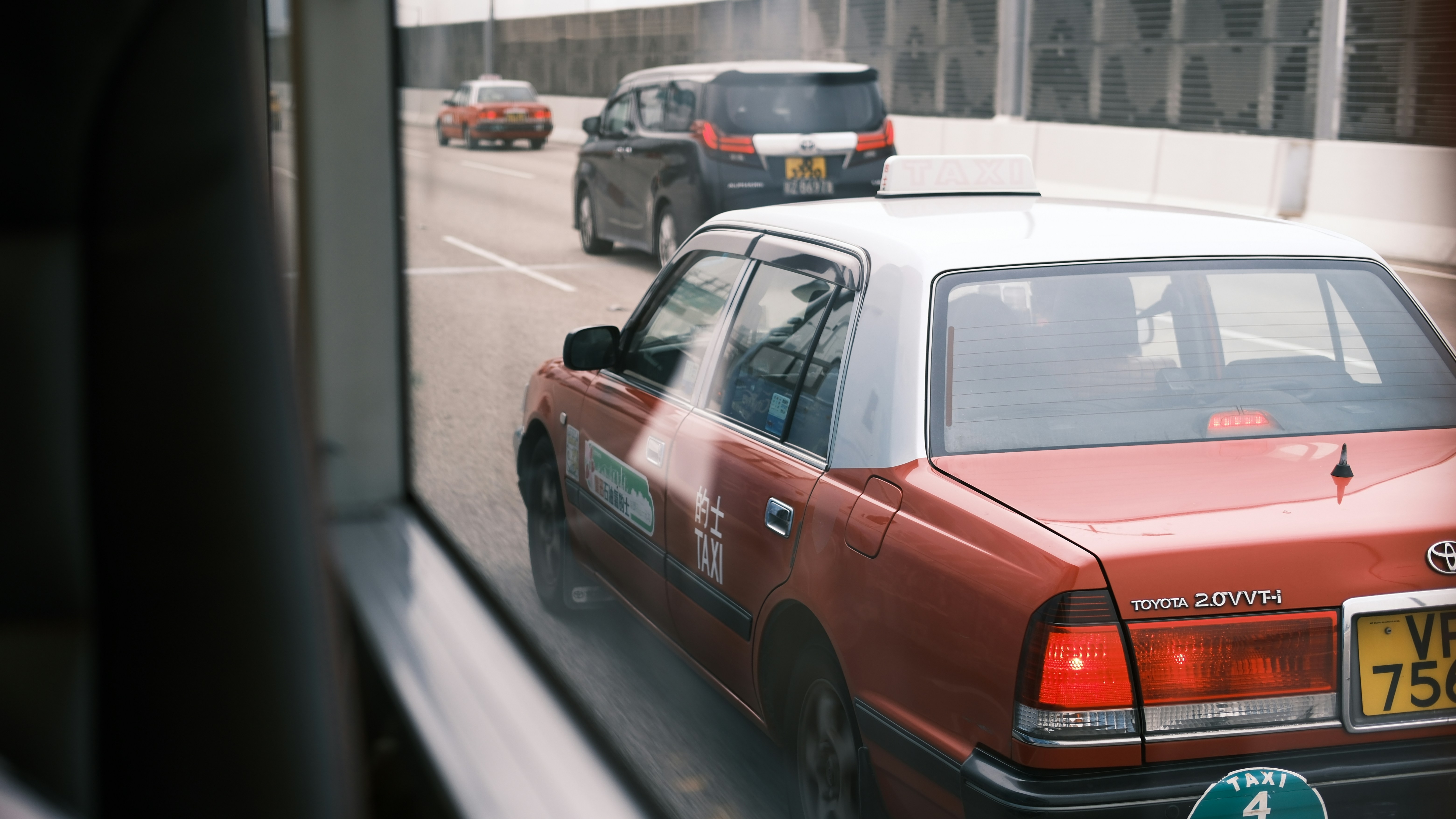 A red taxi cab driving down a street next to a tall building photo ...