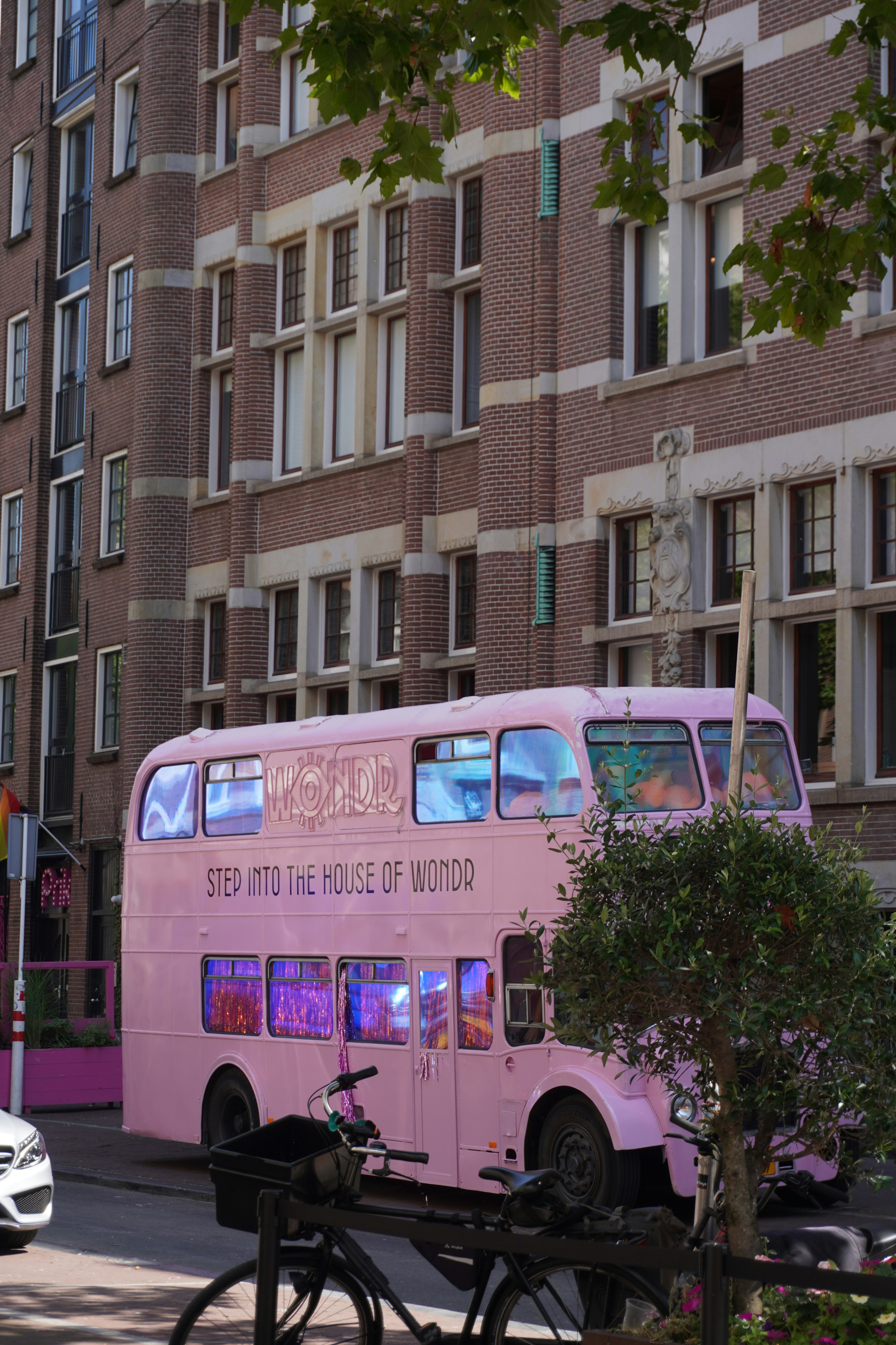 A pink double decker bus driving down a street photo – Free Amsterdam ...
