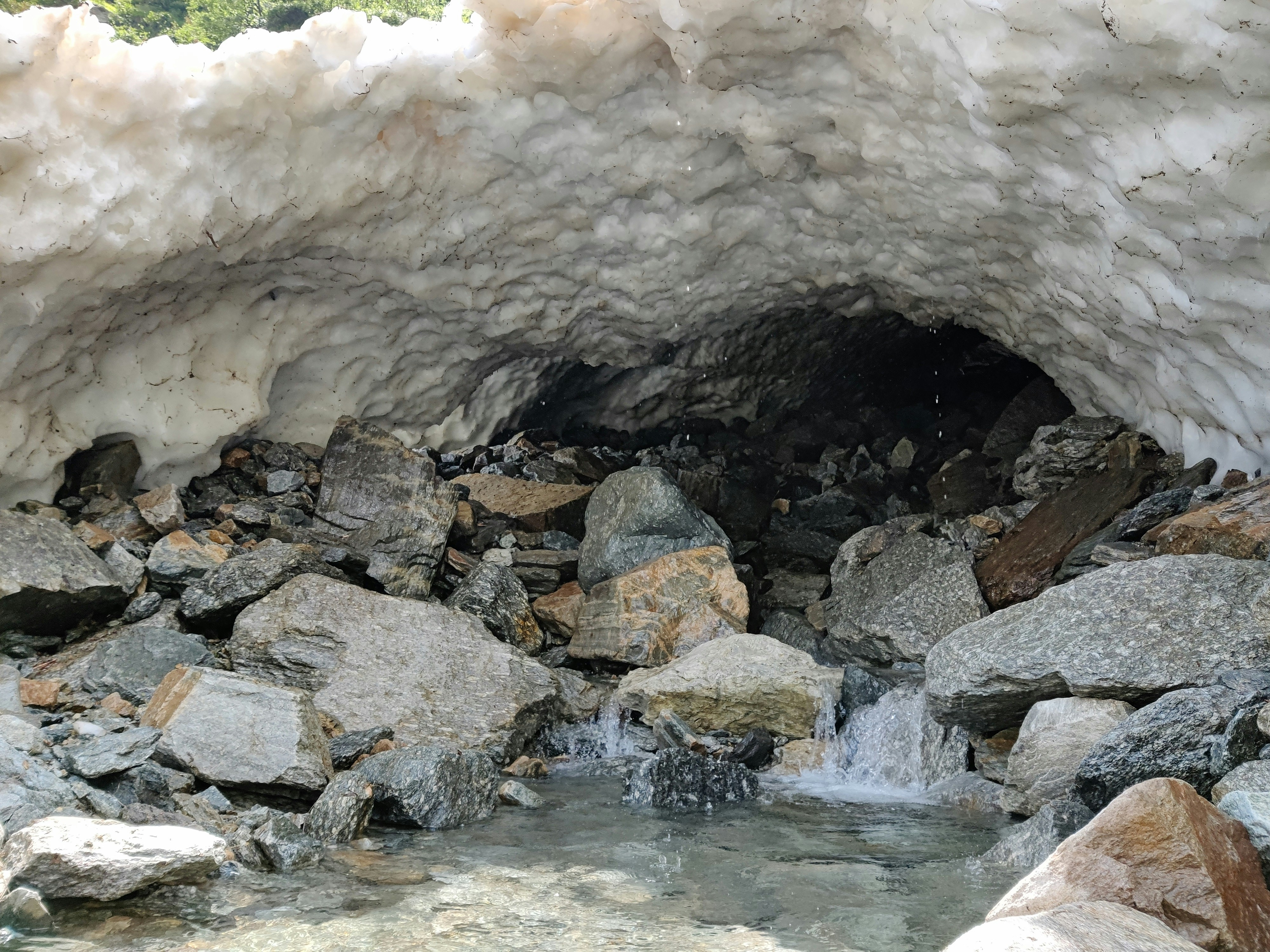 Snowy Cave Entrance Overlooking a Shallow Flow of Mountain Melt