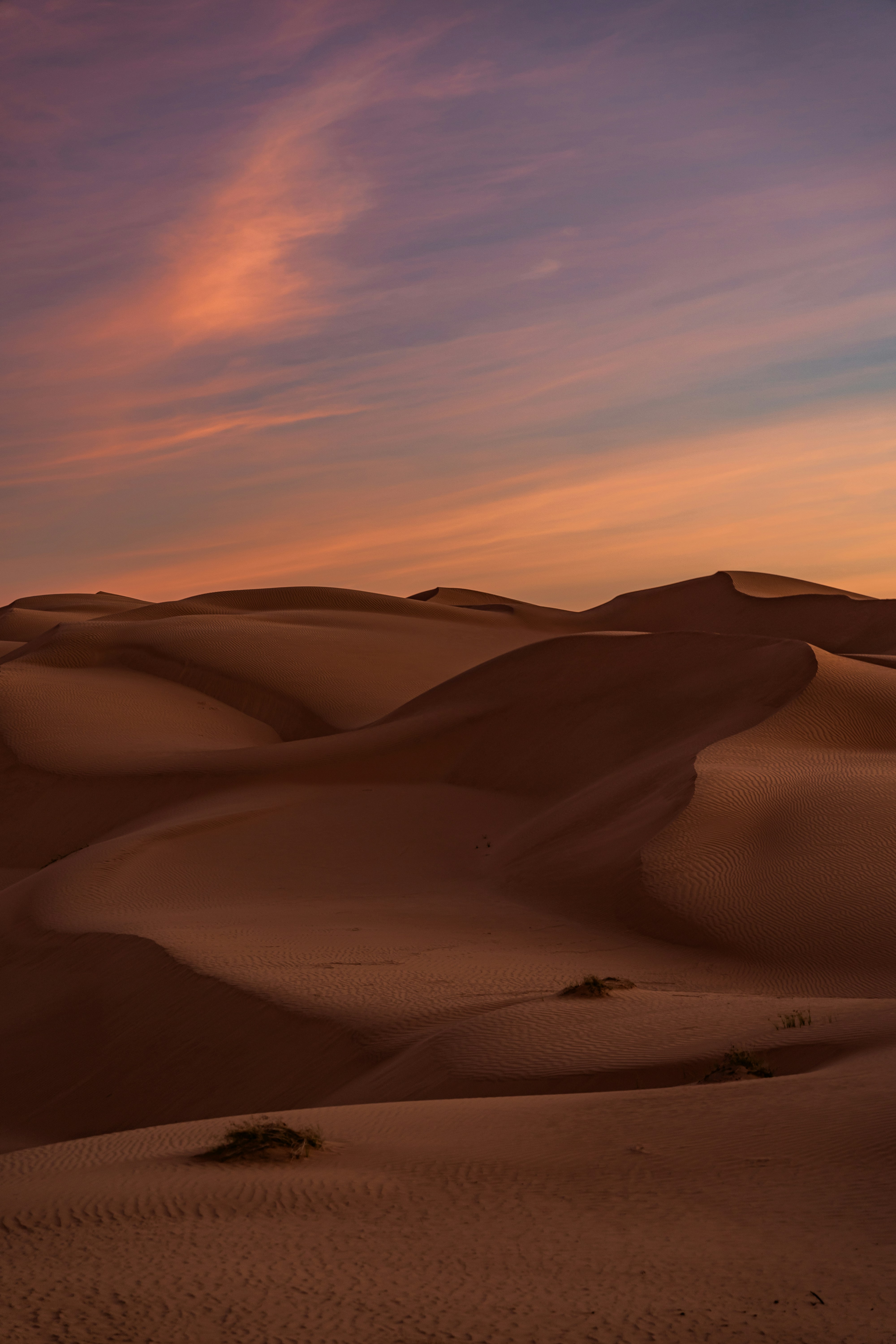 A sunset in the desert with sand dunes