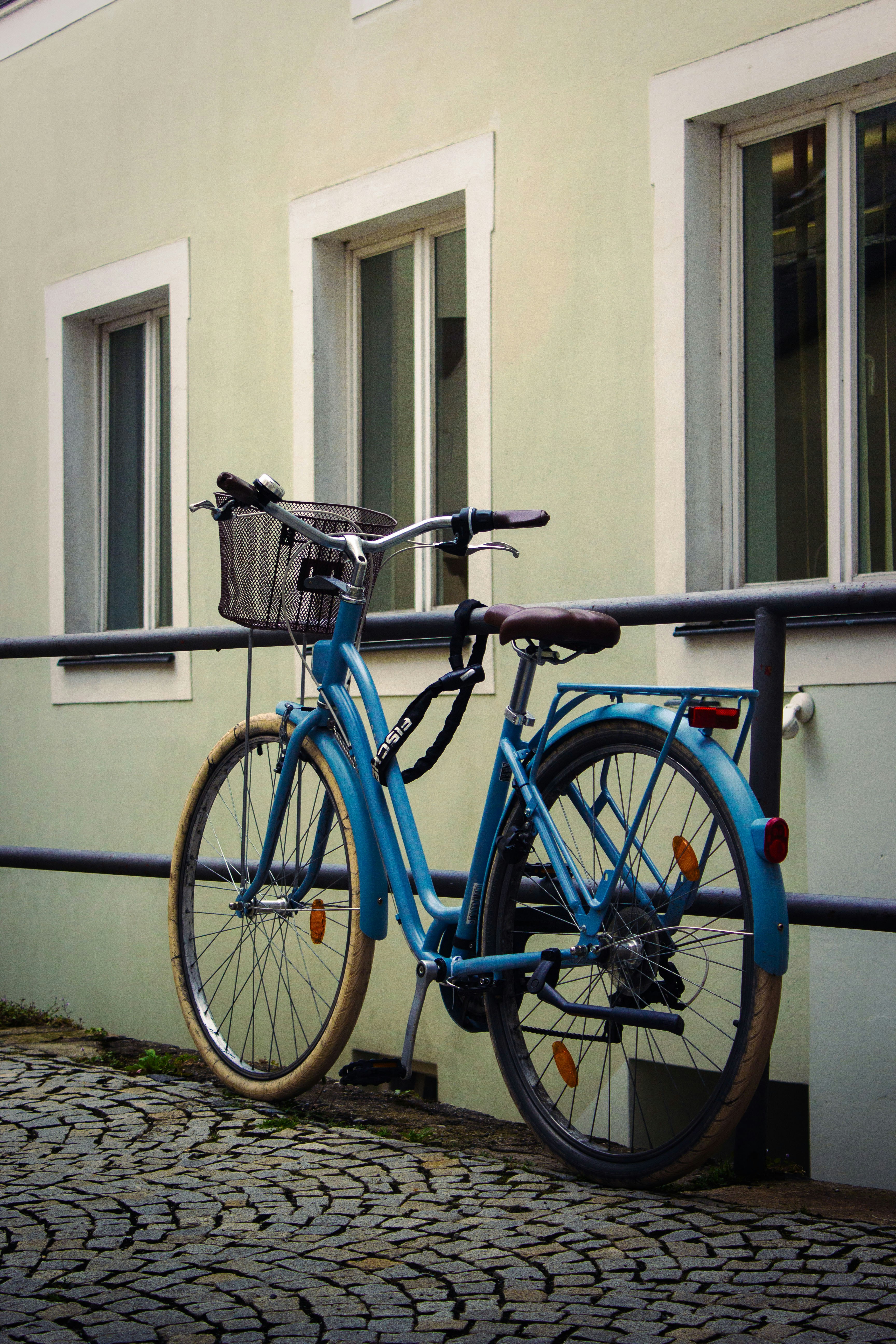 A bicycle chained to a railing next to a building