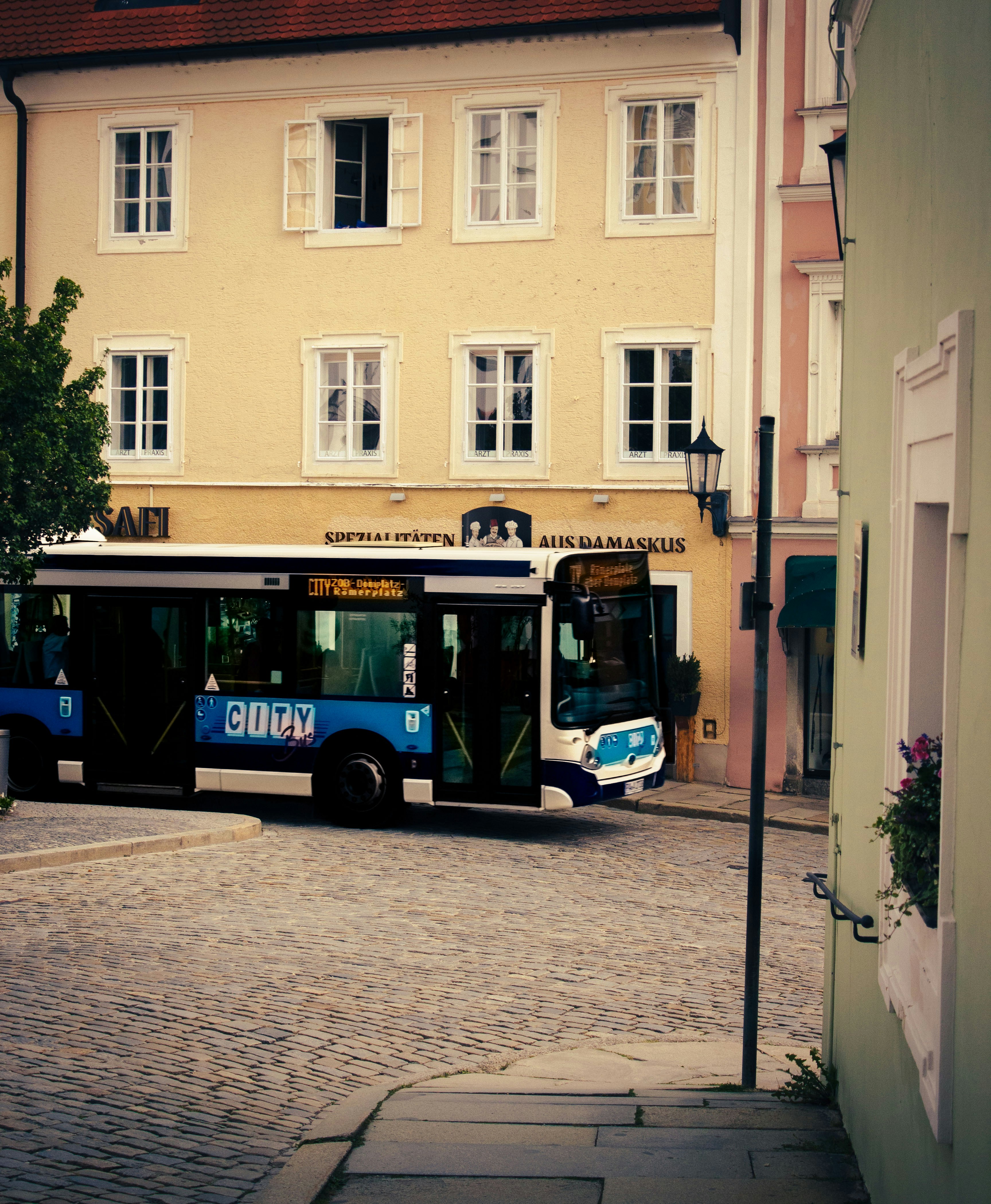 Blue Bus on a Sunlit Cobbled Square: A European Street Scene