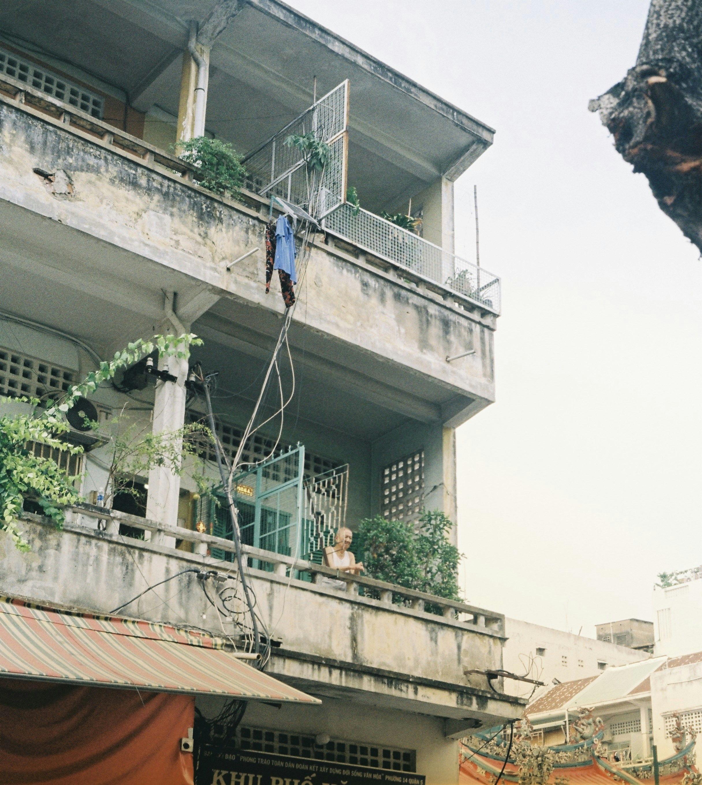 A man is hanging from a balcony on a building