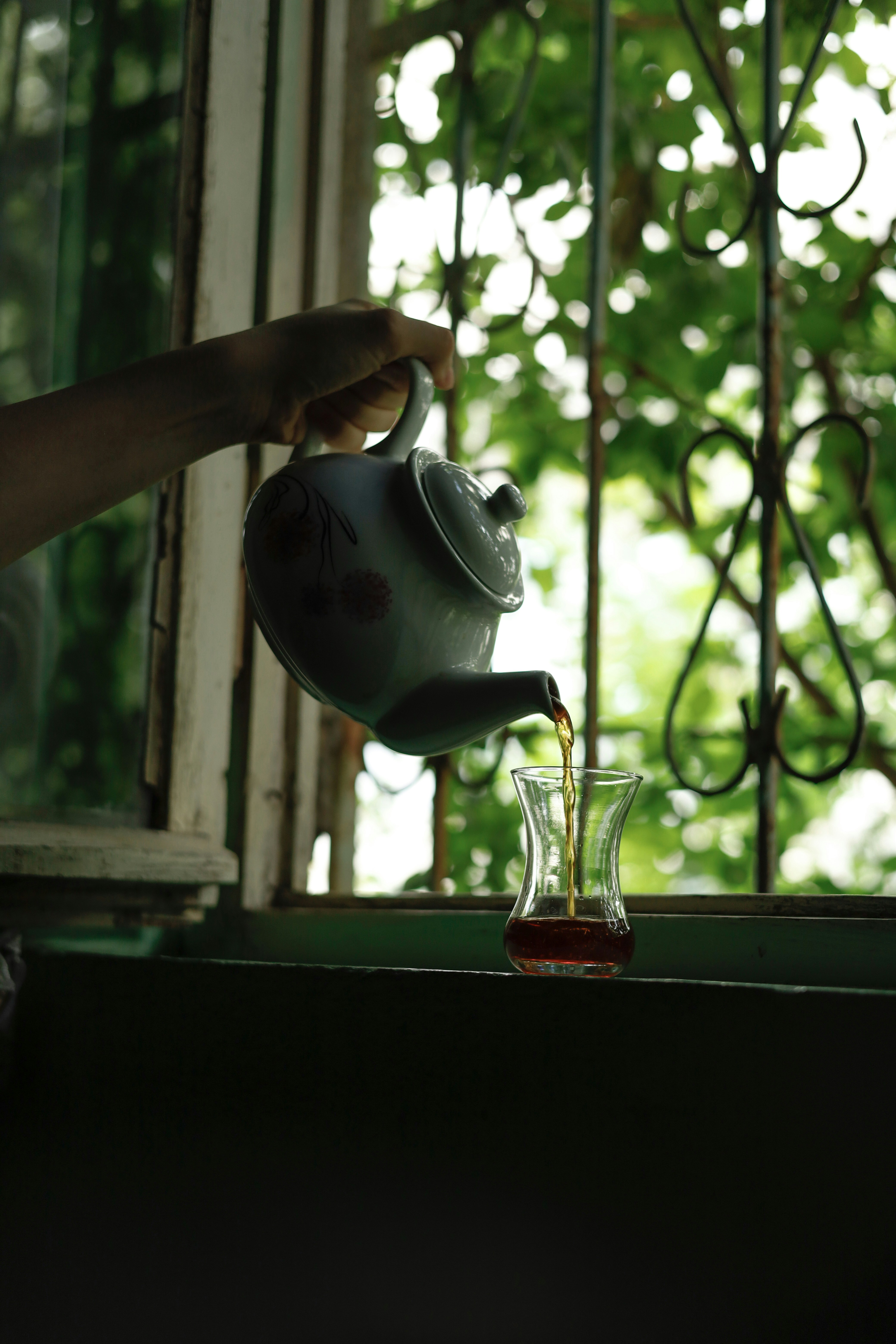 Pour Through the Garden Window: Tea Flow and Light on a Glass Carafe