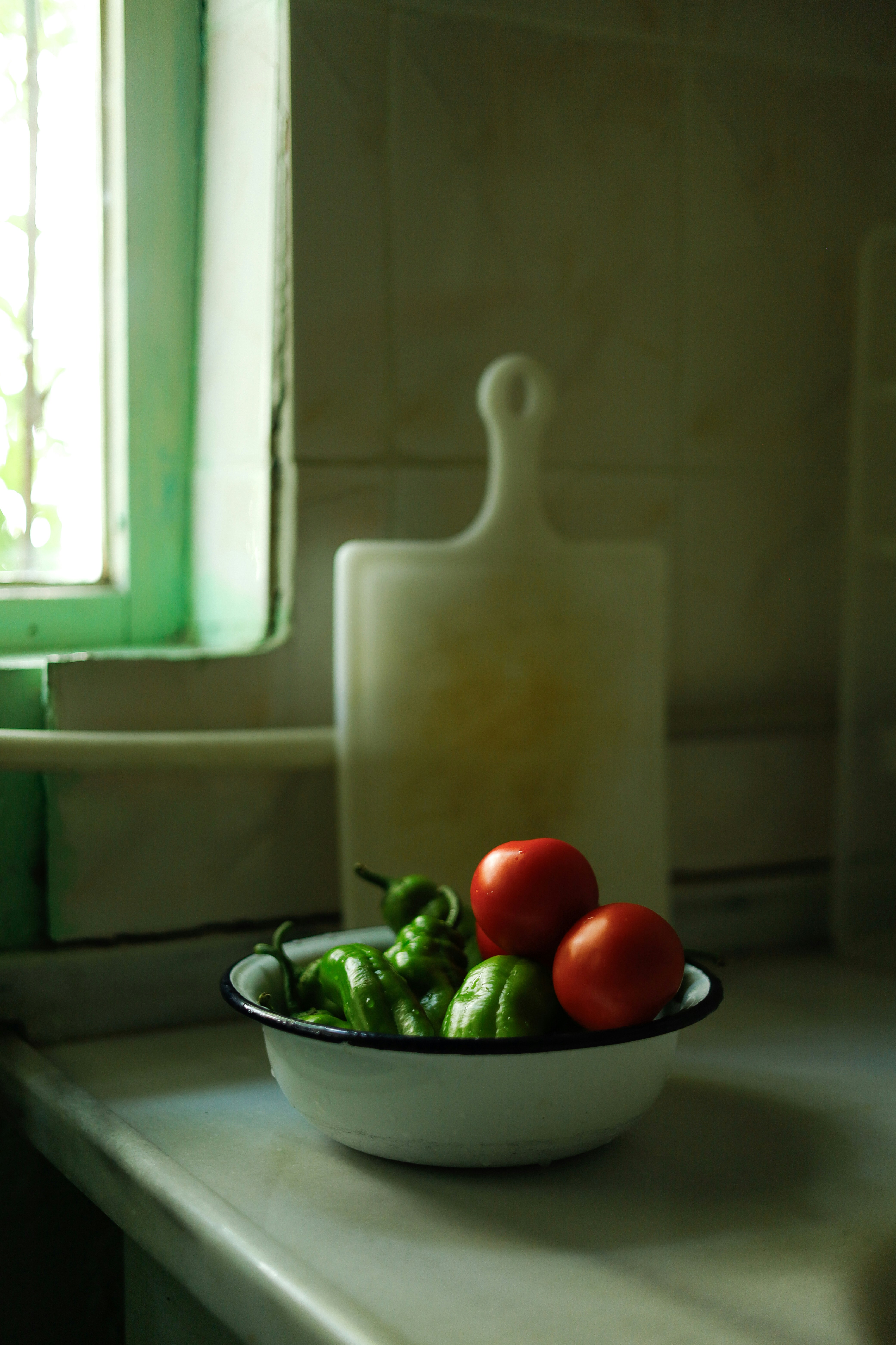 Sunlit Still Life: Green Peppers Meet Red Tomatoes on a Quiet Kitchen Counter