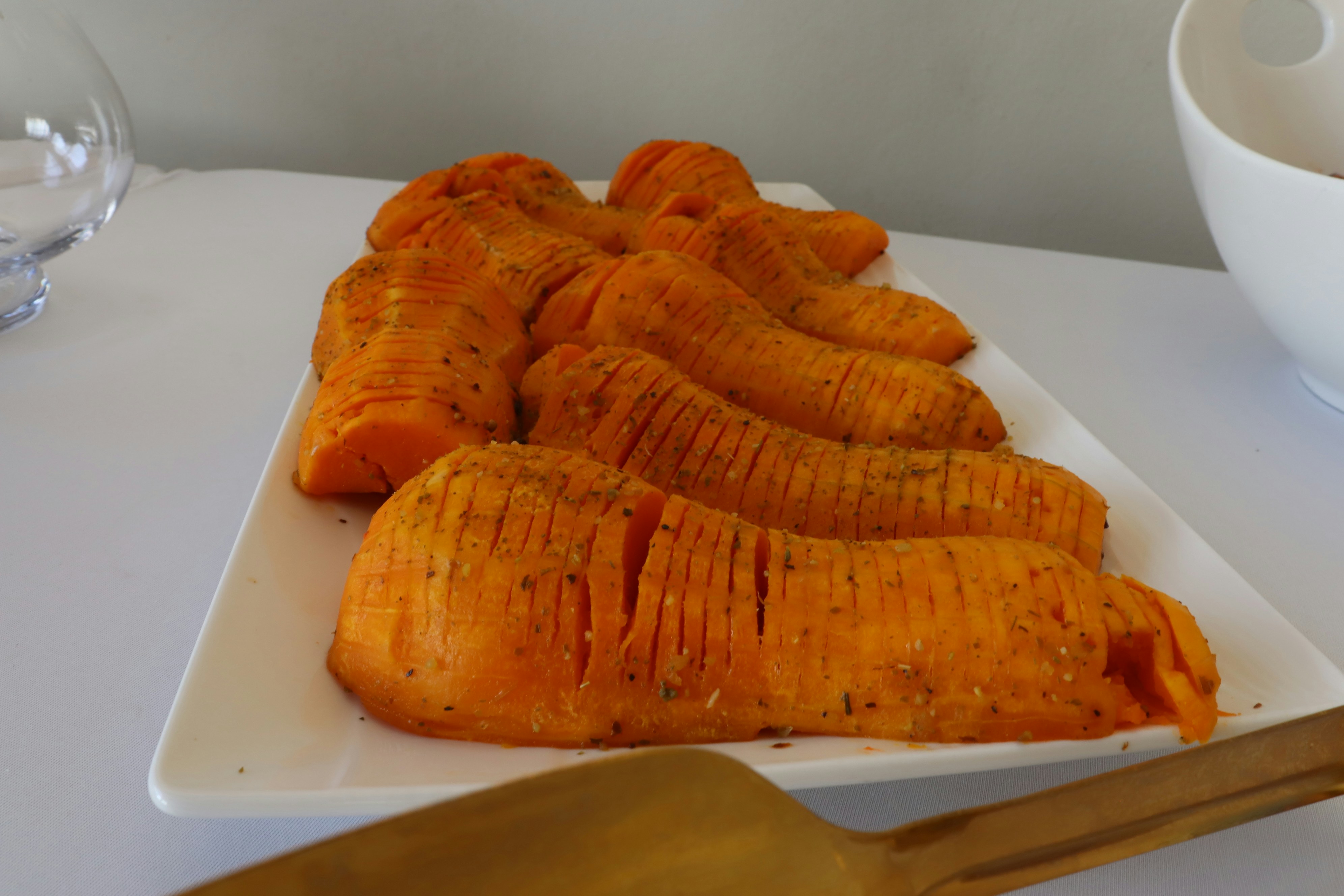 Herb-Studded Orange Pastry Rolls on a Sleek White Plate