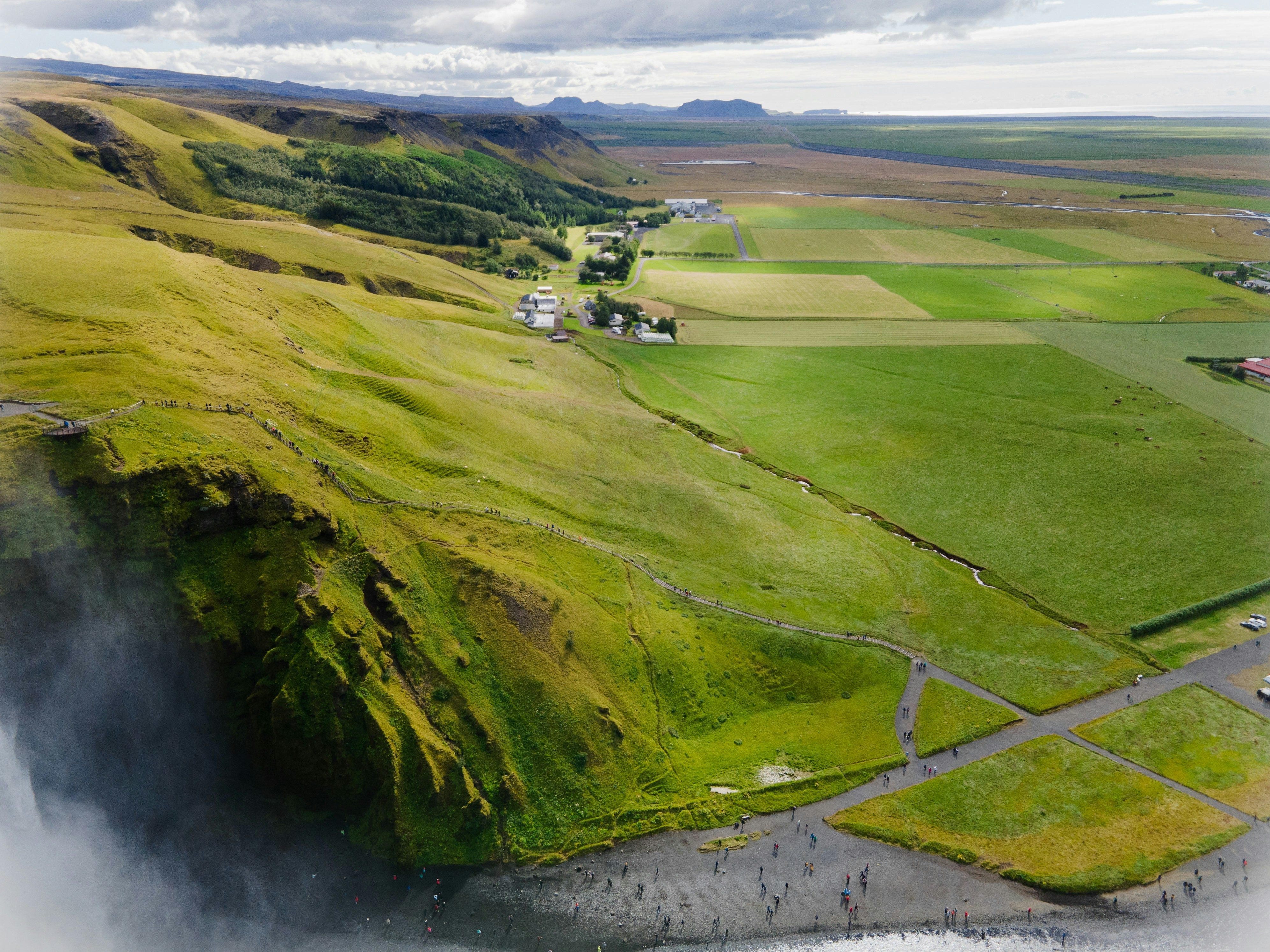 Patchwork Cliffside: Verdant Slopes Meet Misty Shore in a Drone View