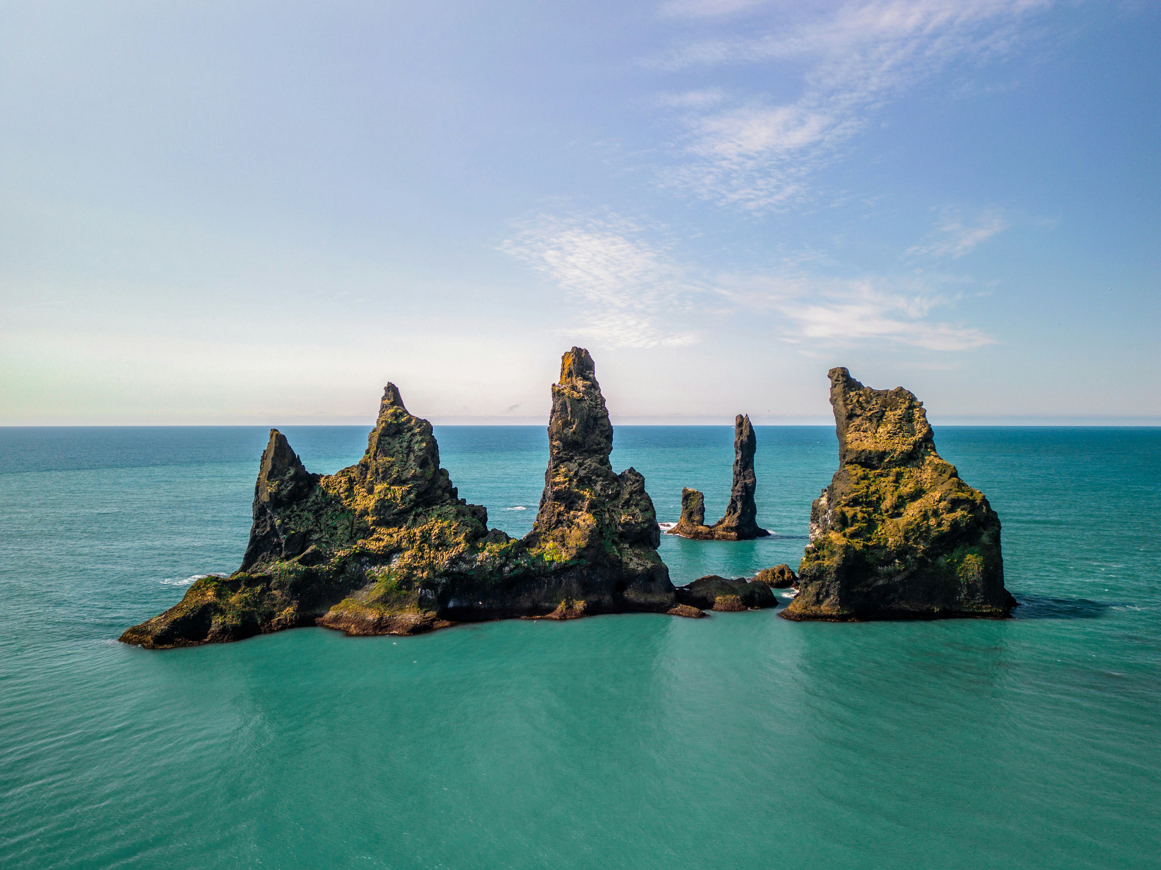 A group of rocks sticking out of the ocean photo – Free Wallpaper Image ...