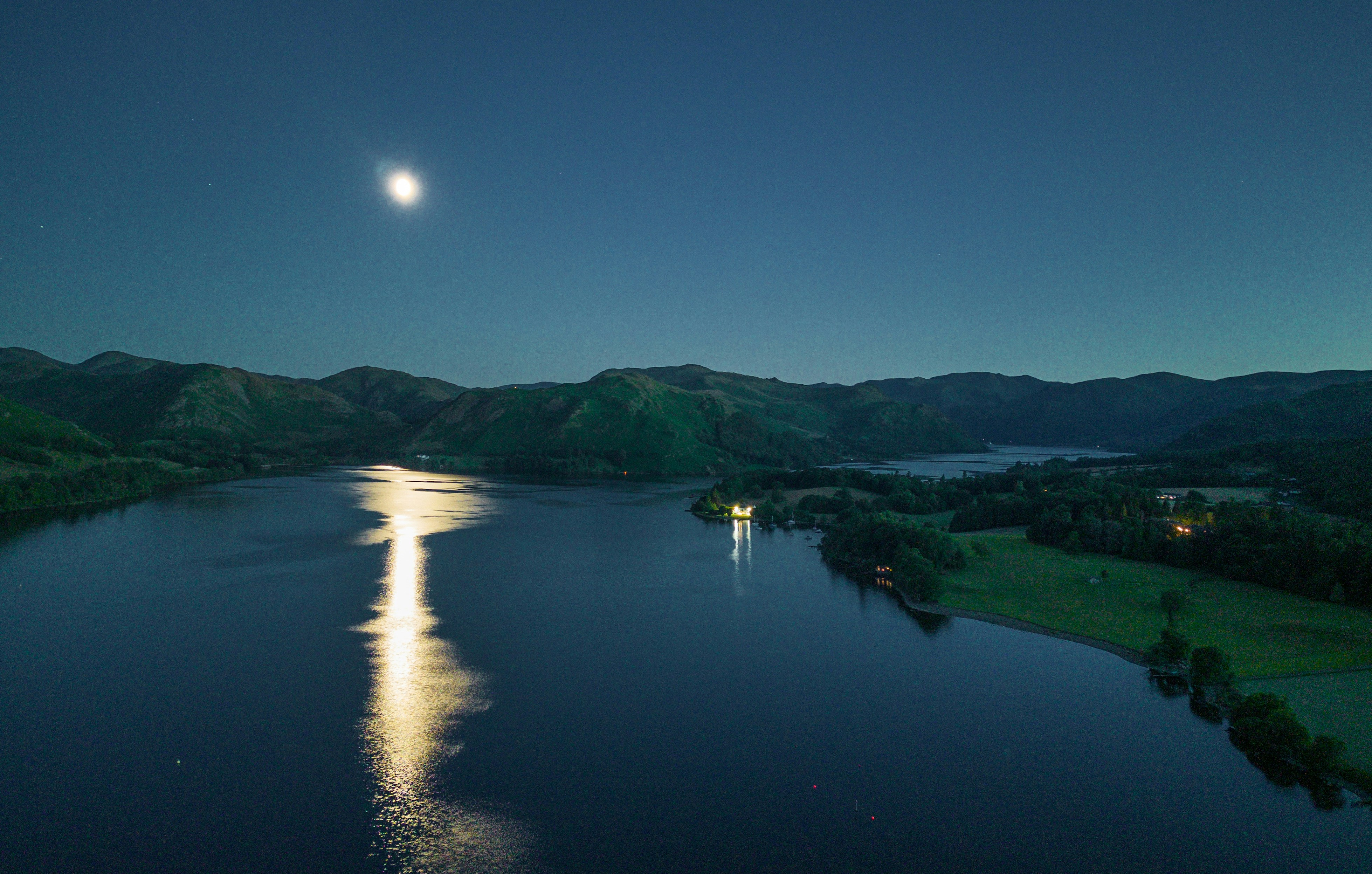 A full moon rising over a lake with mountains in the background photo ...