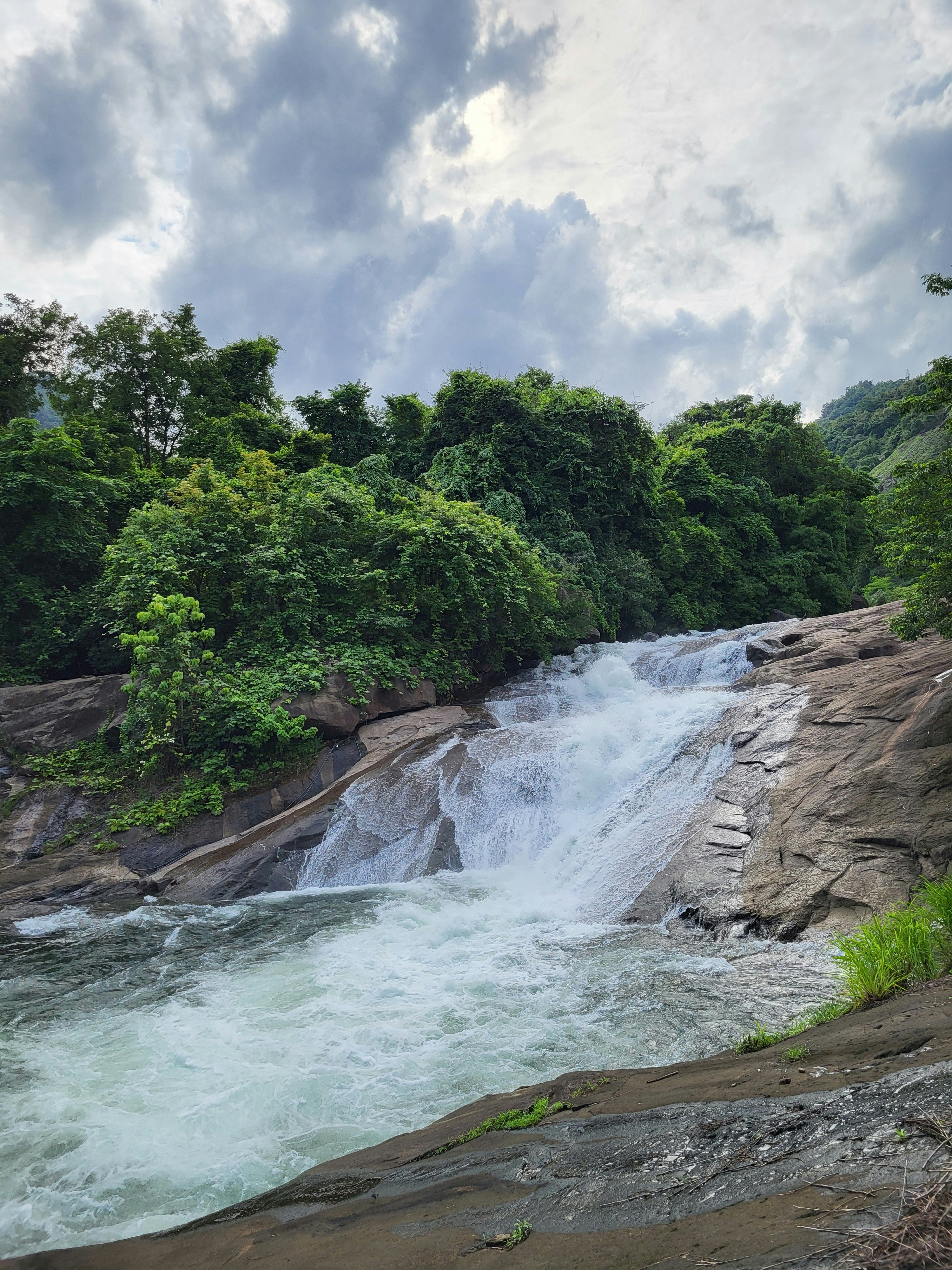 A man standing on a rock next to a waterfall photo – Free Adyanpara ...