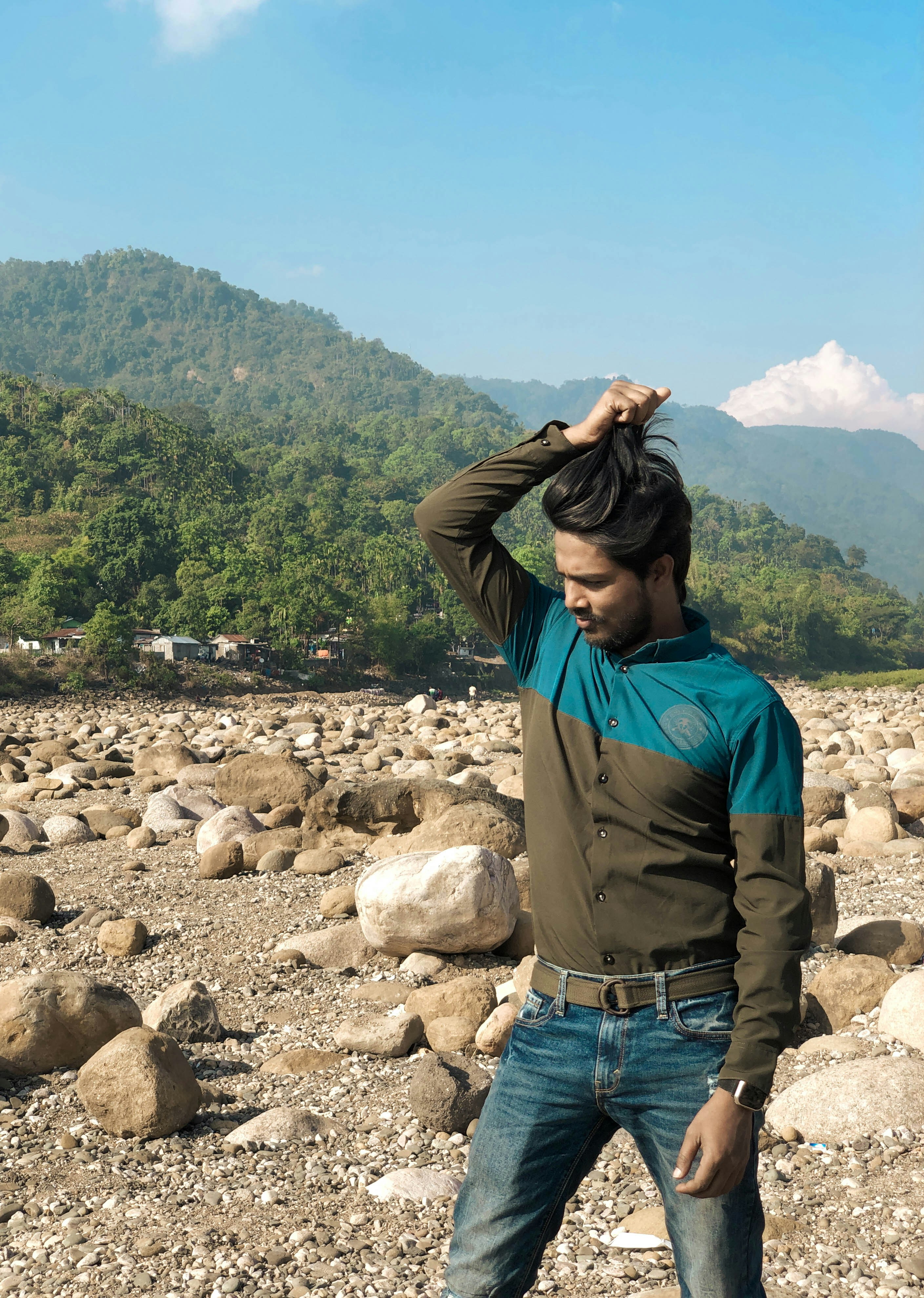 Pose on the Rocky Riverbank: A casual stride under a sunlit sky
