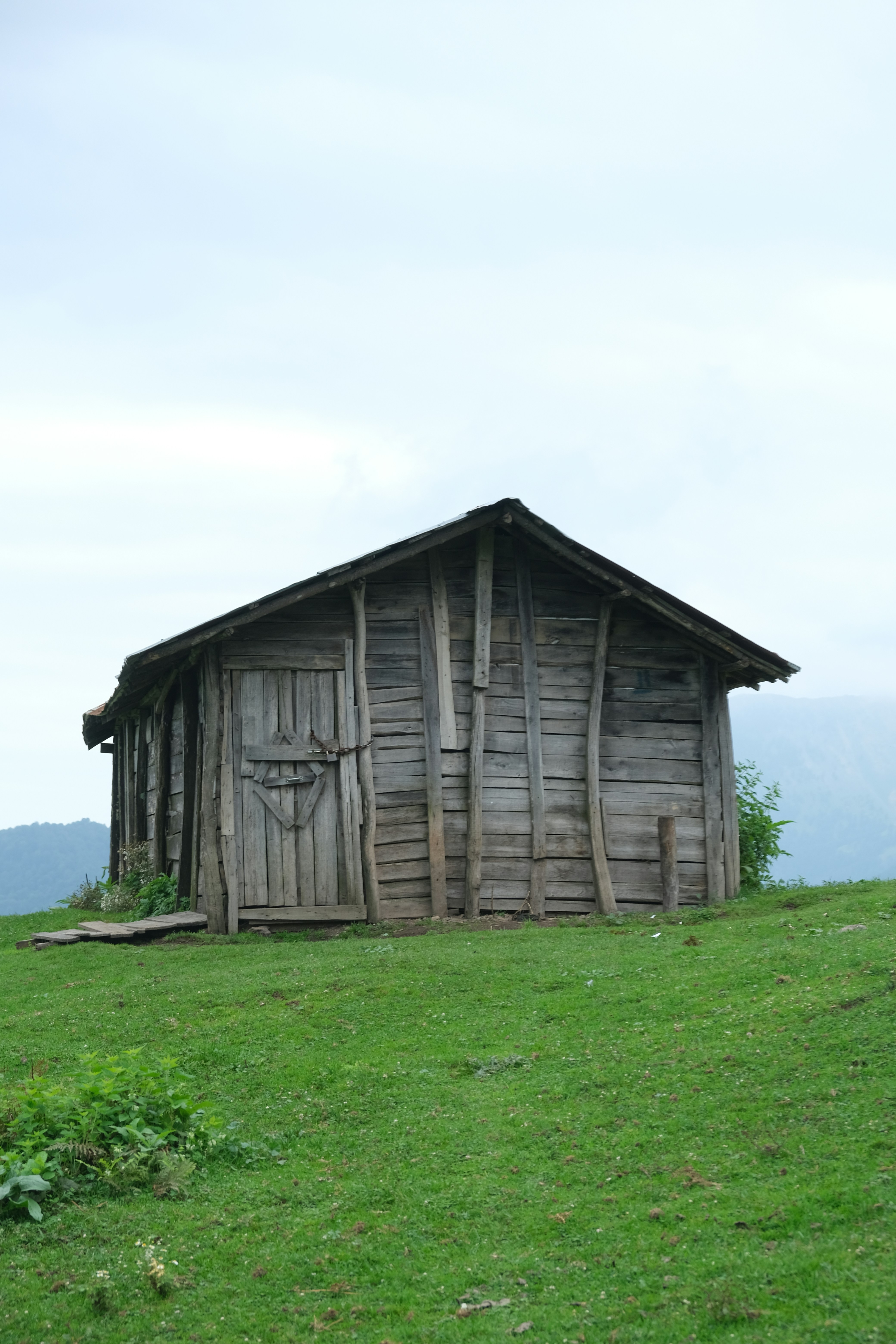 Weathered Cabin on a Quiet Hillside Beneath a Pale Sky