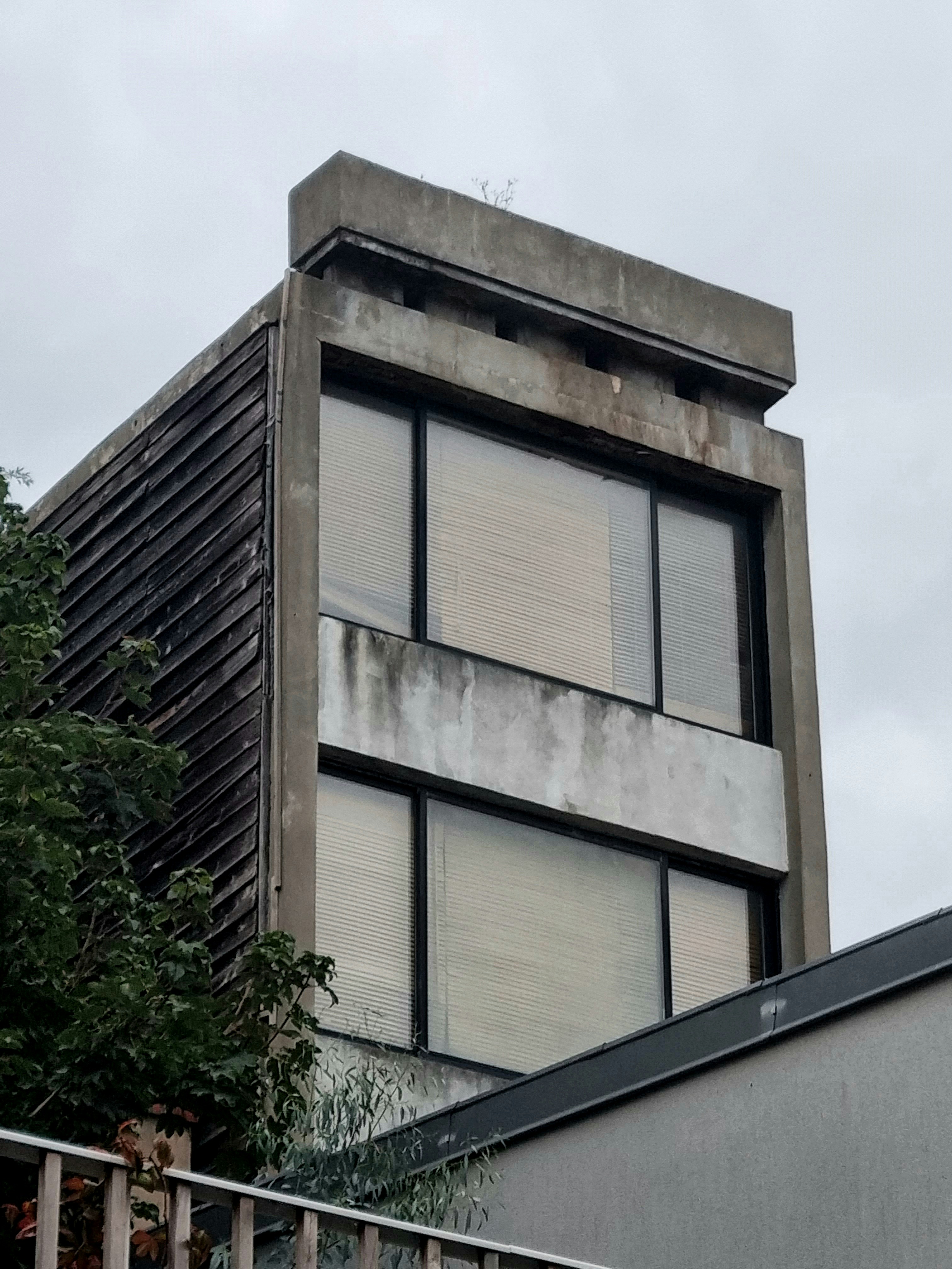 Brutalist Corner: A Weathered Concrete Tower Against an Overcast Sky