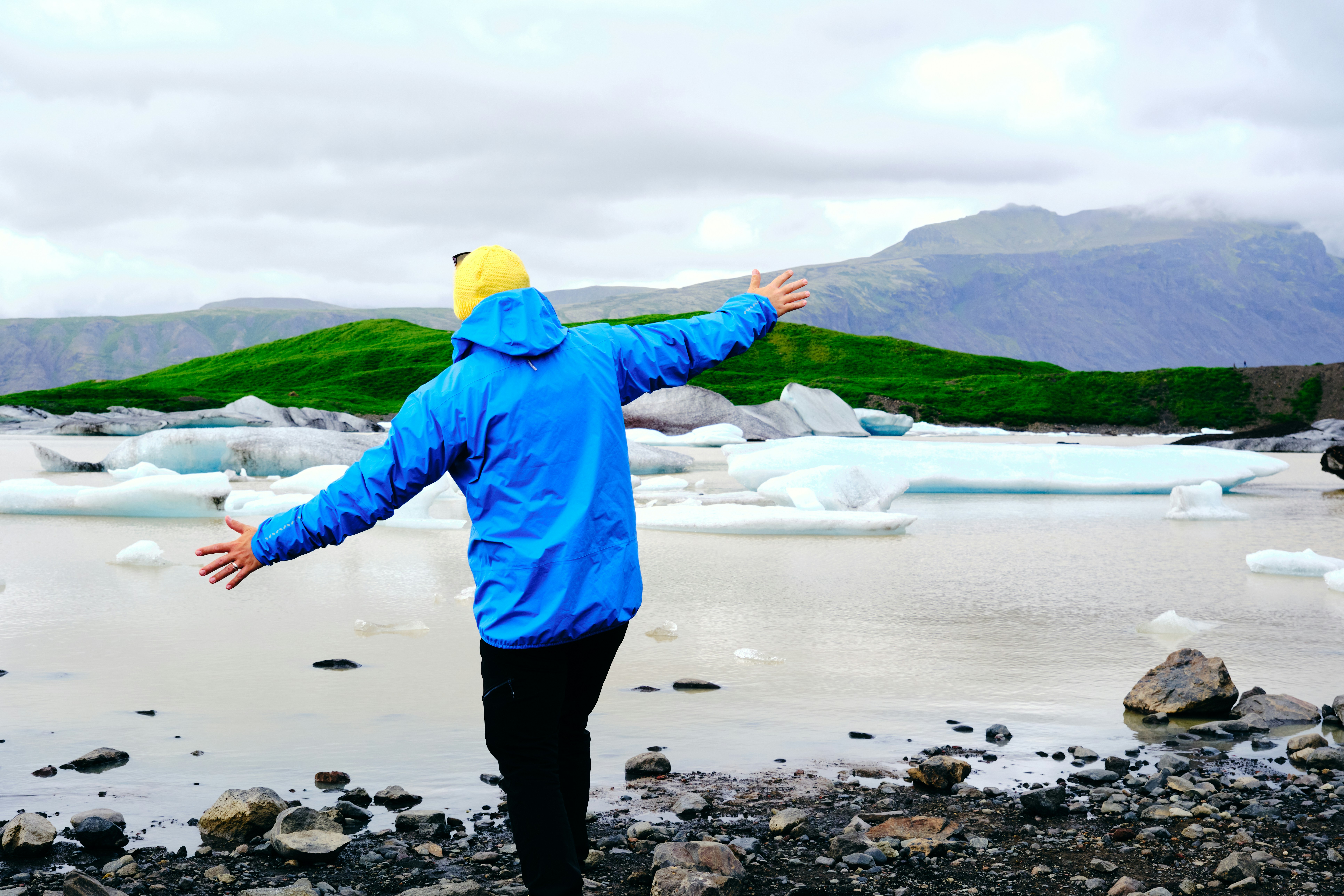 Arctic Embrace: A Blue-Jacket Figure Stretches Against a Glacial Shore