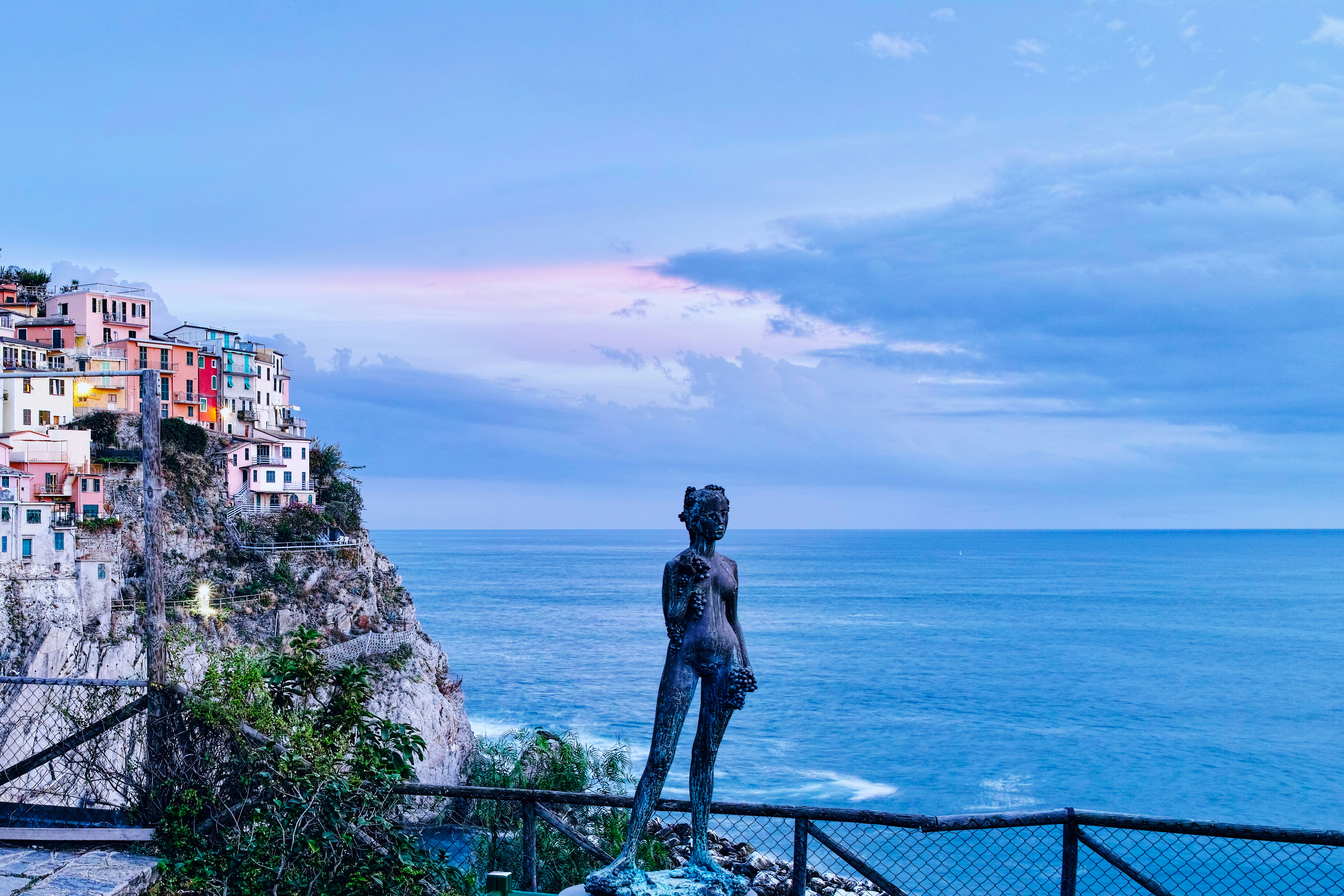 Cliffside Sentinel: A Bronze Figure Overlooking a Colorful Coastal Horizon