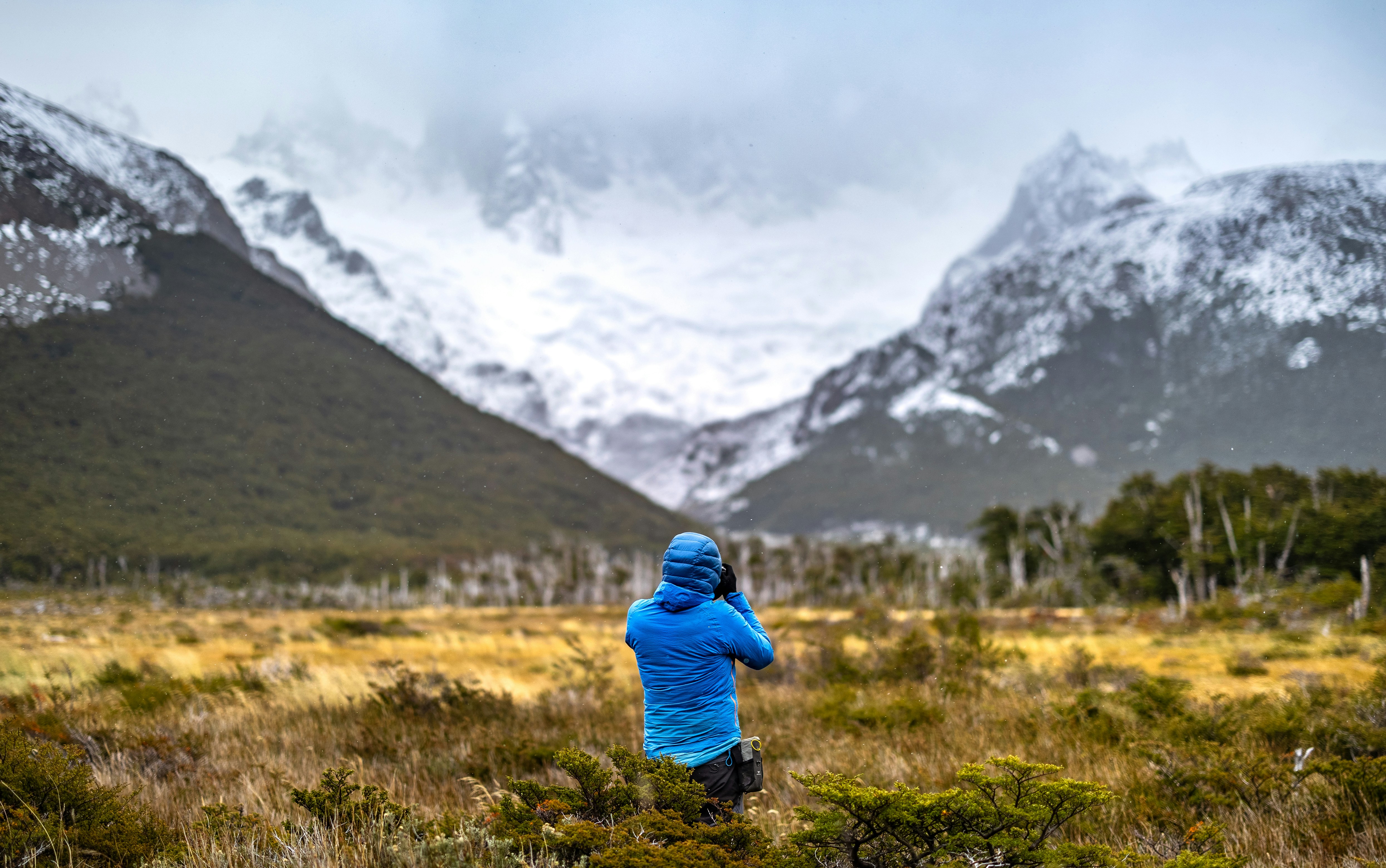 A person standing in a field with mountains in the background photo ...
