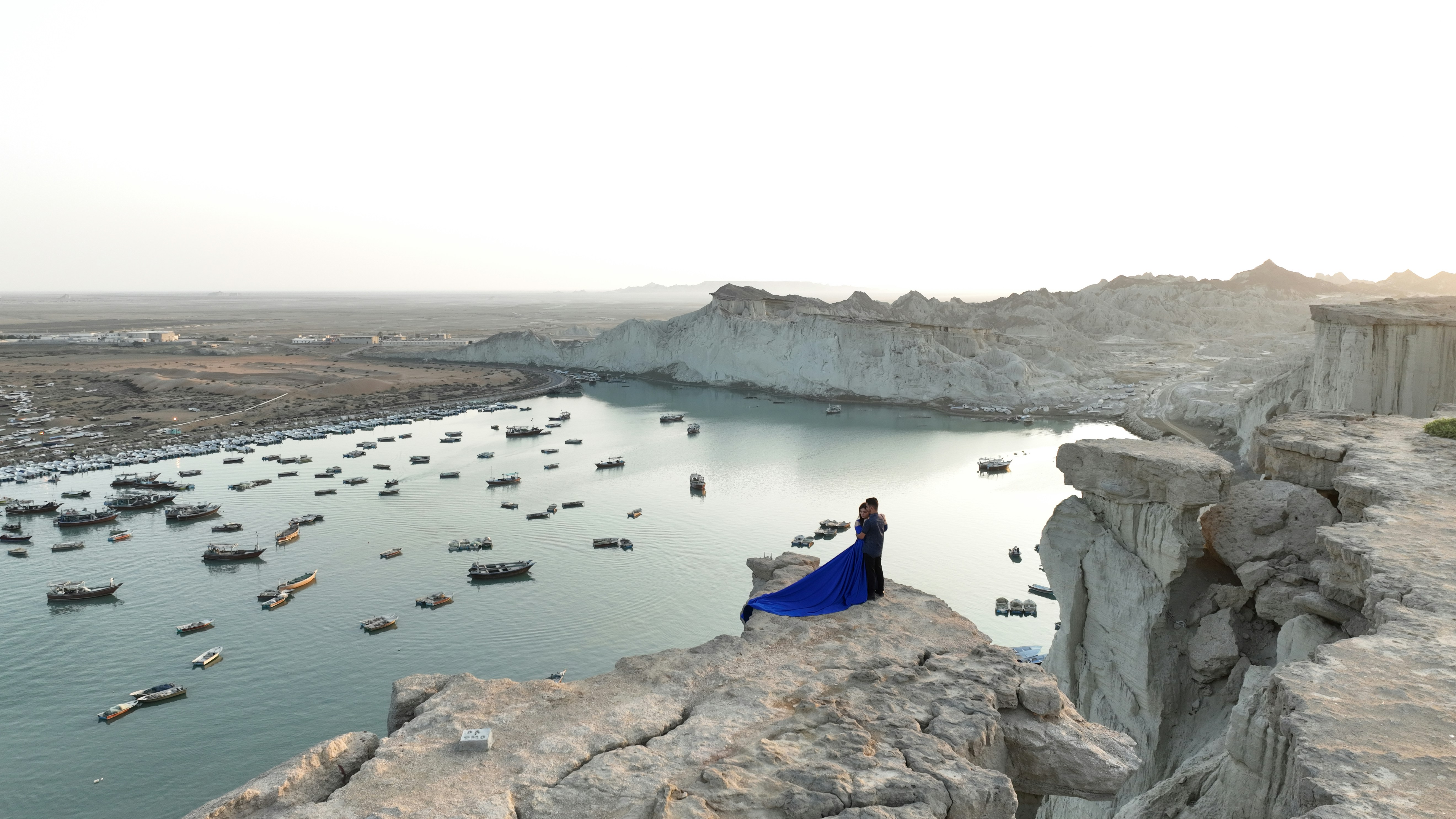 A person standing on top of a cliff next to a body of water