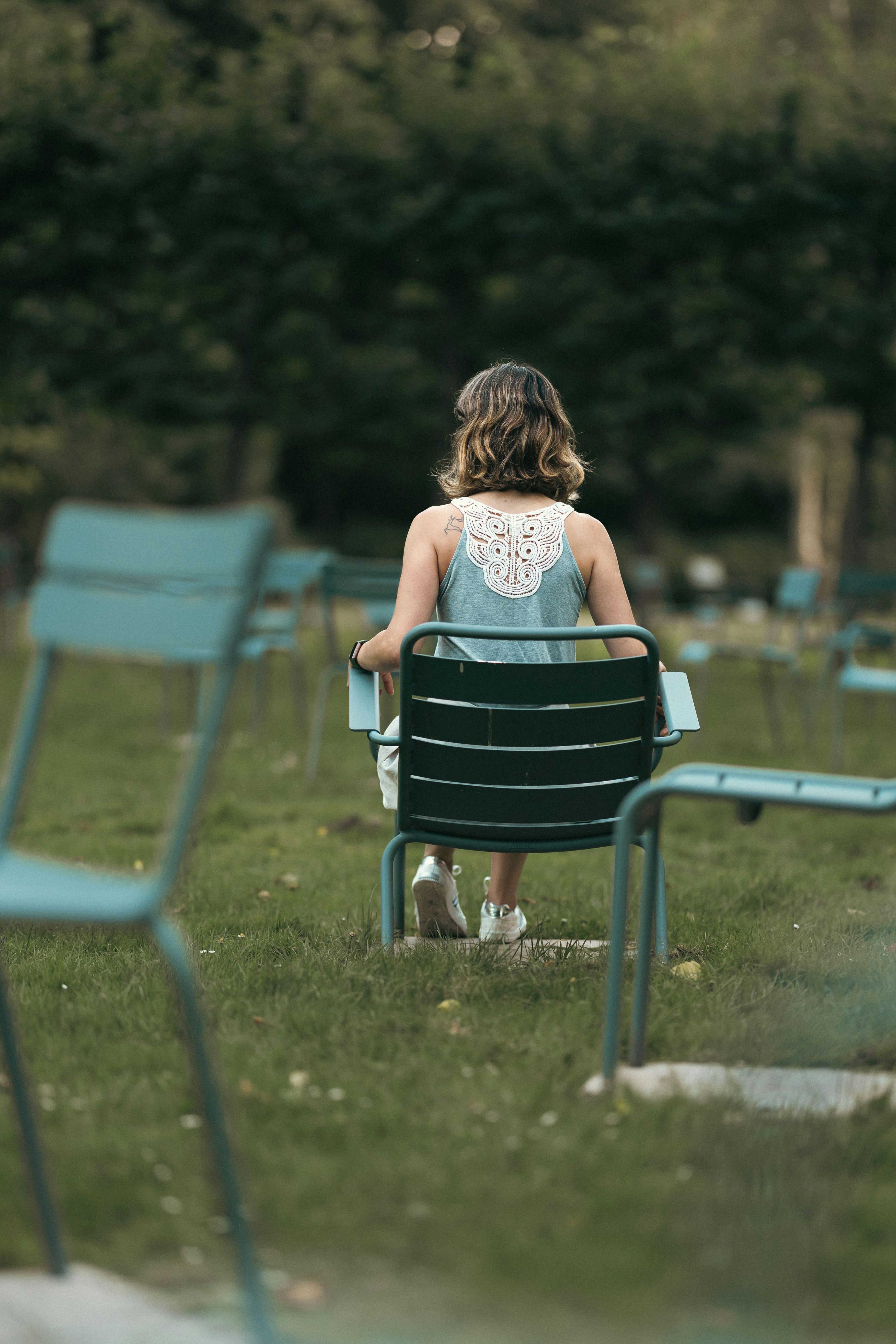 Between Teal Chairs: Quiet Portrait in a Sunlit Park