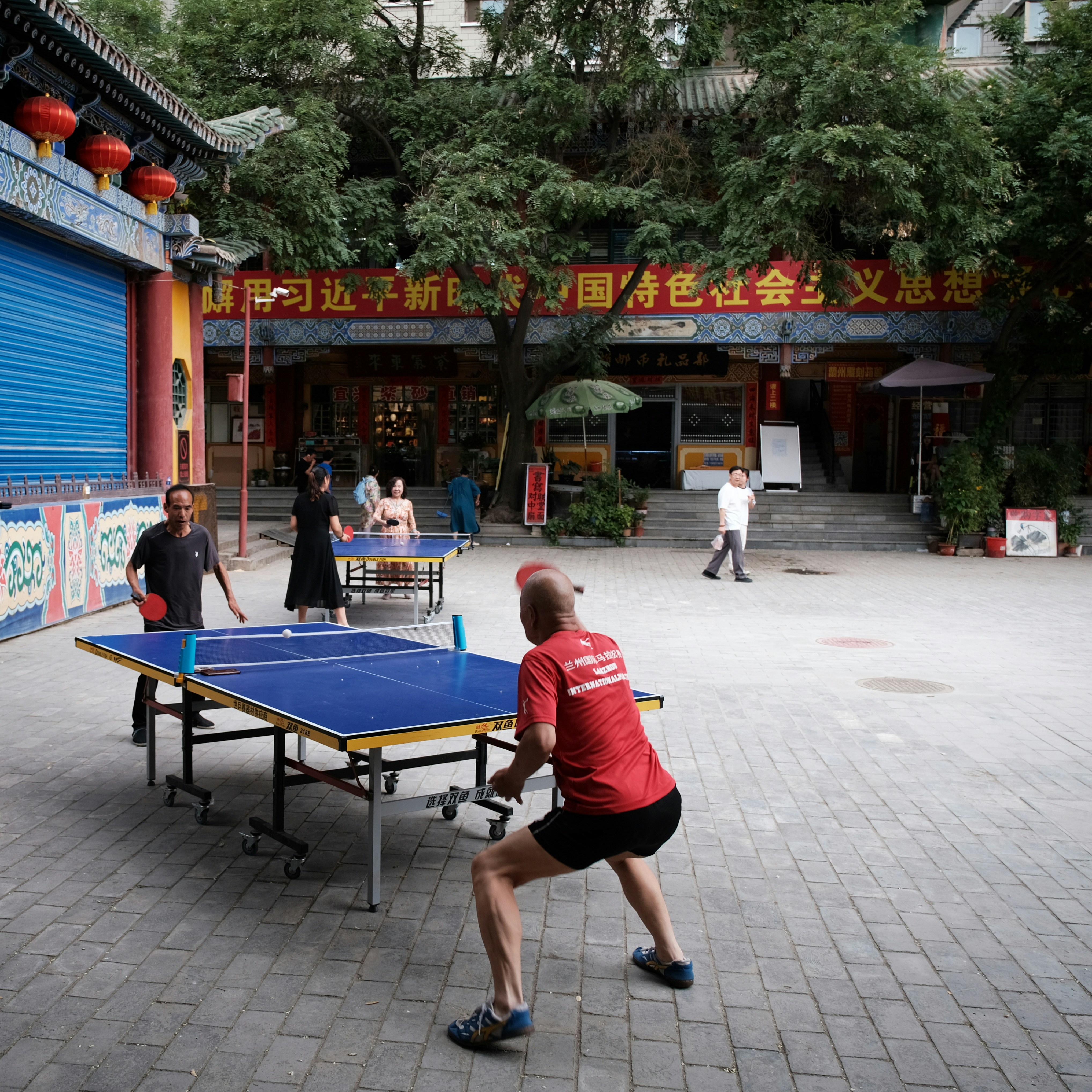 A man is playing ping pong in a courtyard photo – Free China Image on ...