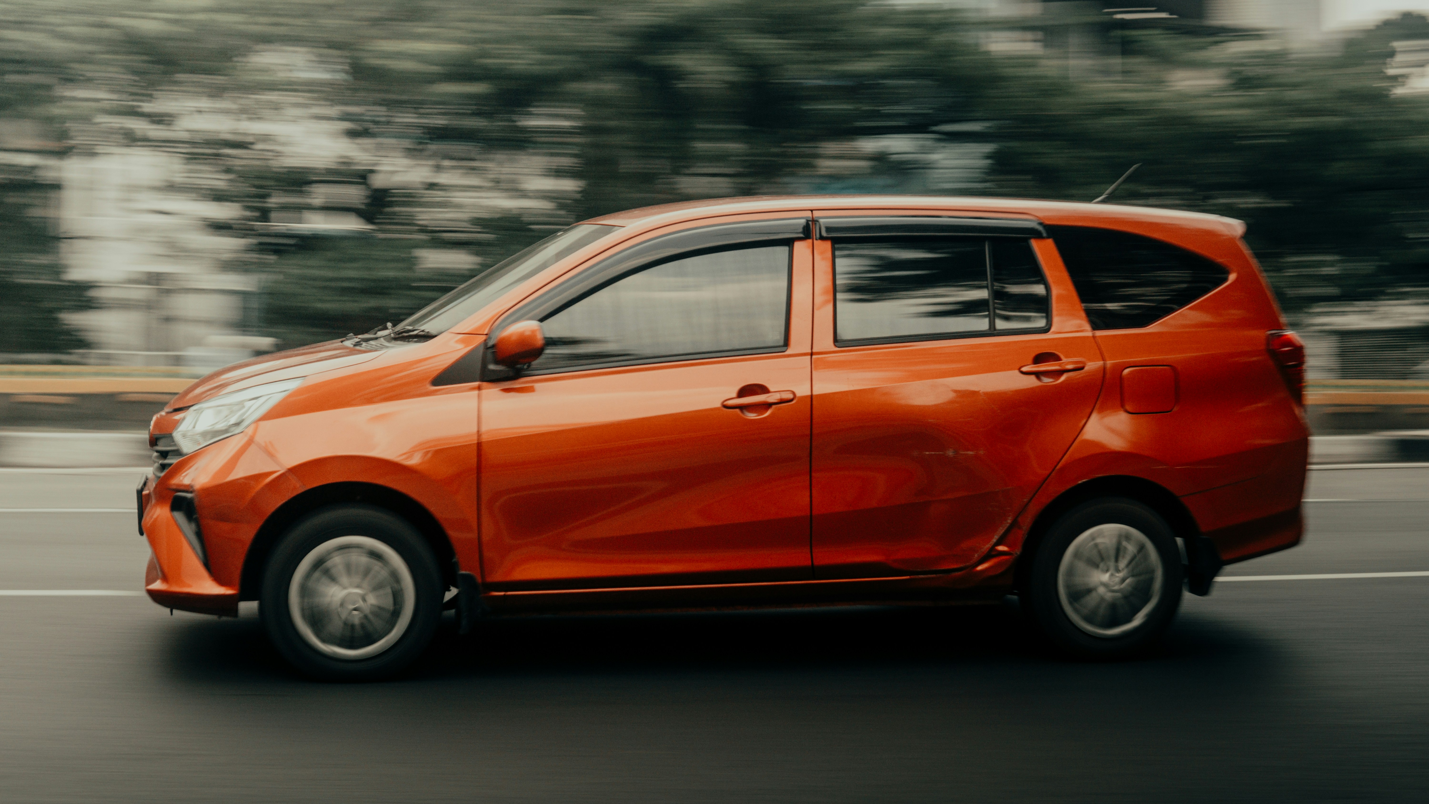 A small orange car driving down a street photo – Free Indonesia Image ...