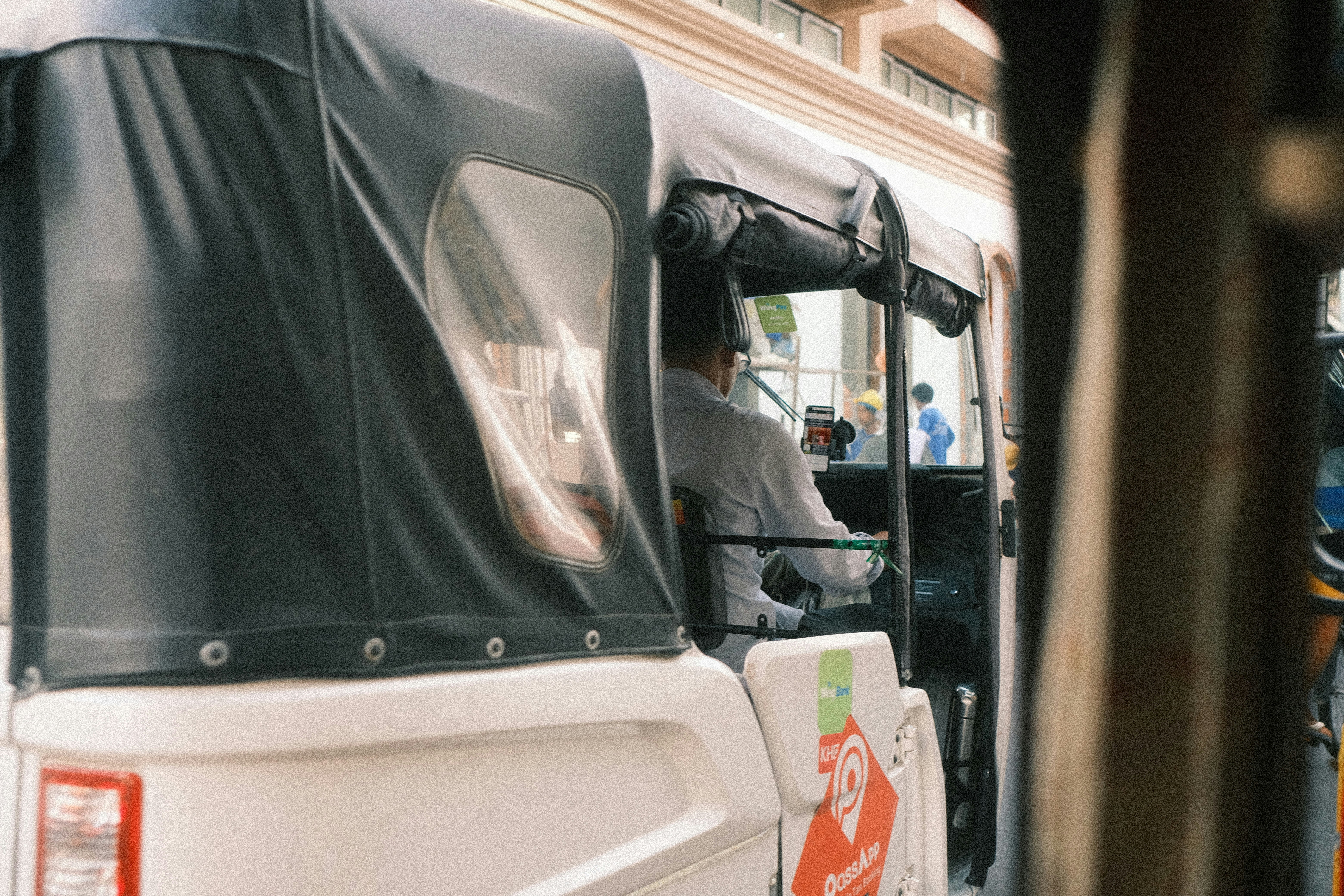 A tuk-tuk navigates a bustling city street, capturing the essence of local urban life.