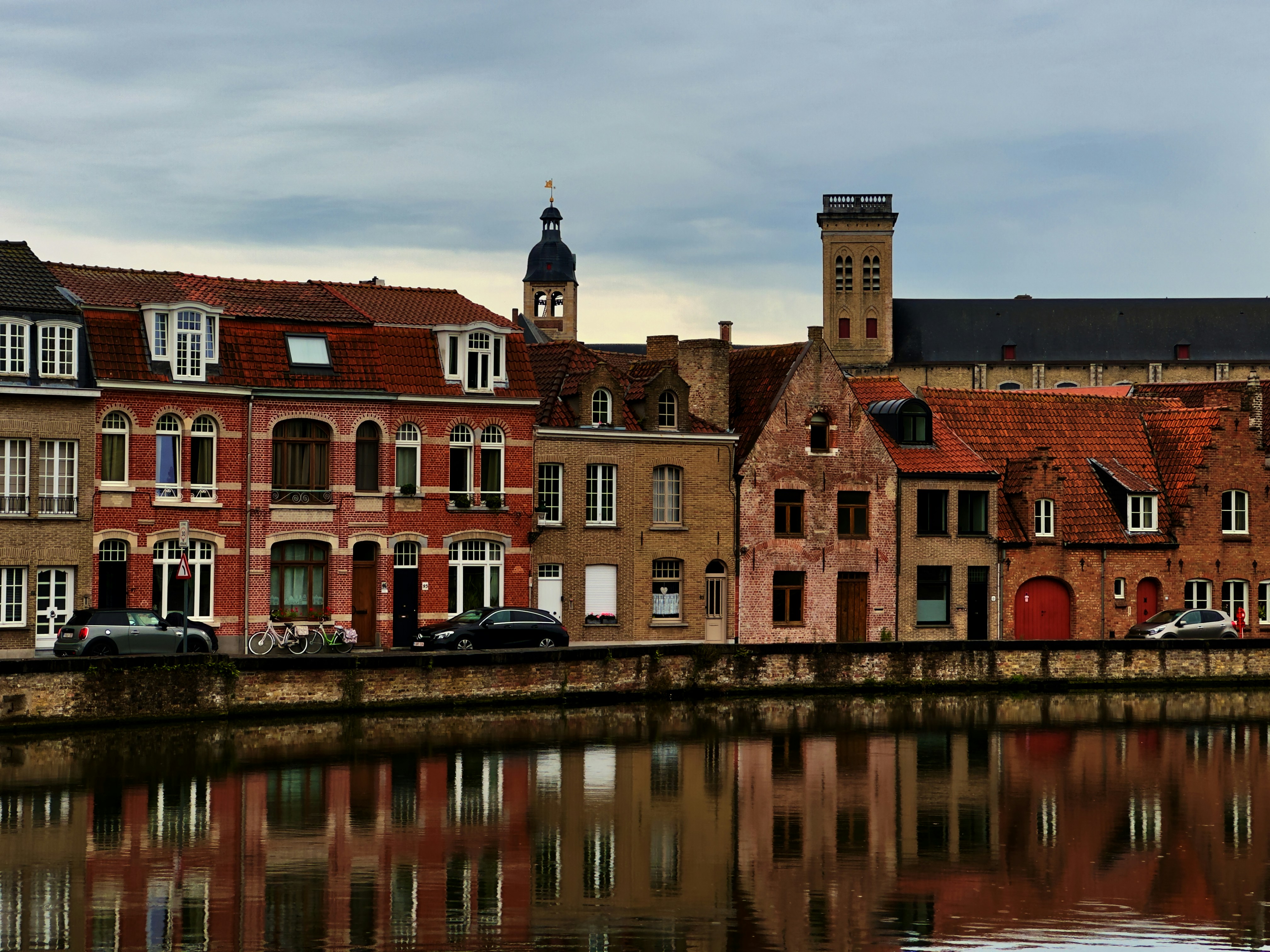 Charming canal-side architecture in Bruges, showcasing a mix of historical buildings with distinct facades and reflections in the water.