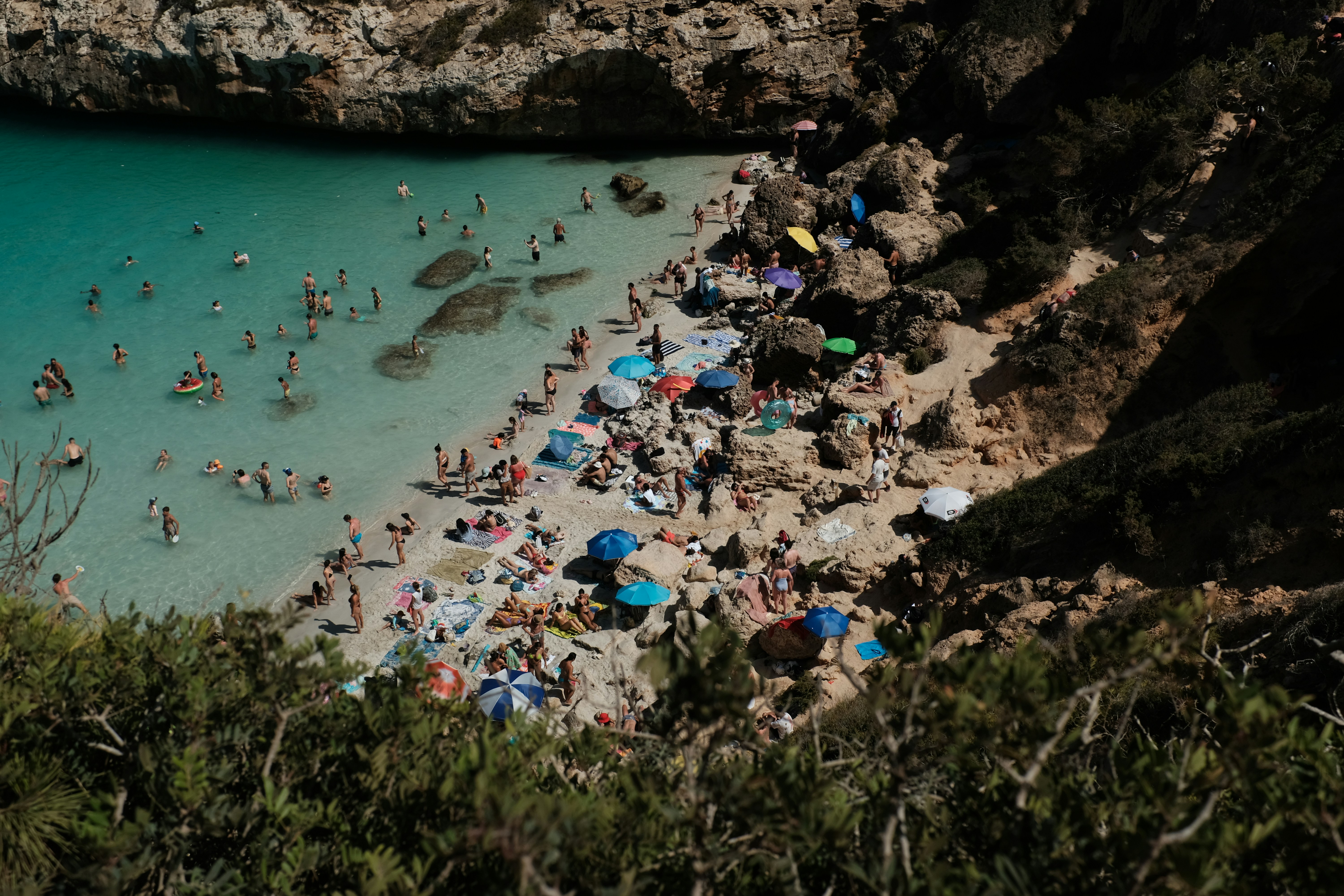 A group of people standing on top of a beach next to a body of water