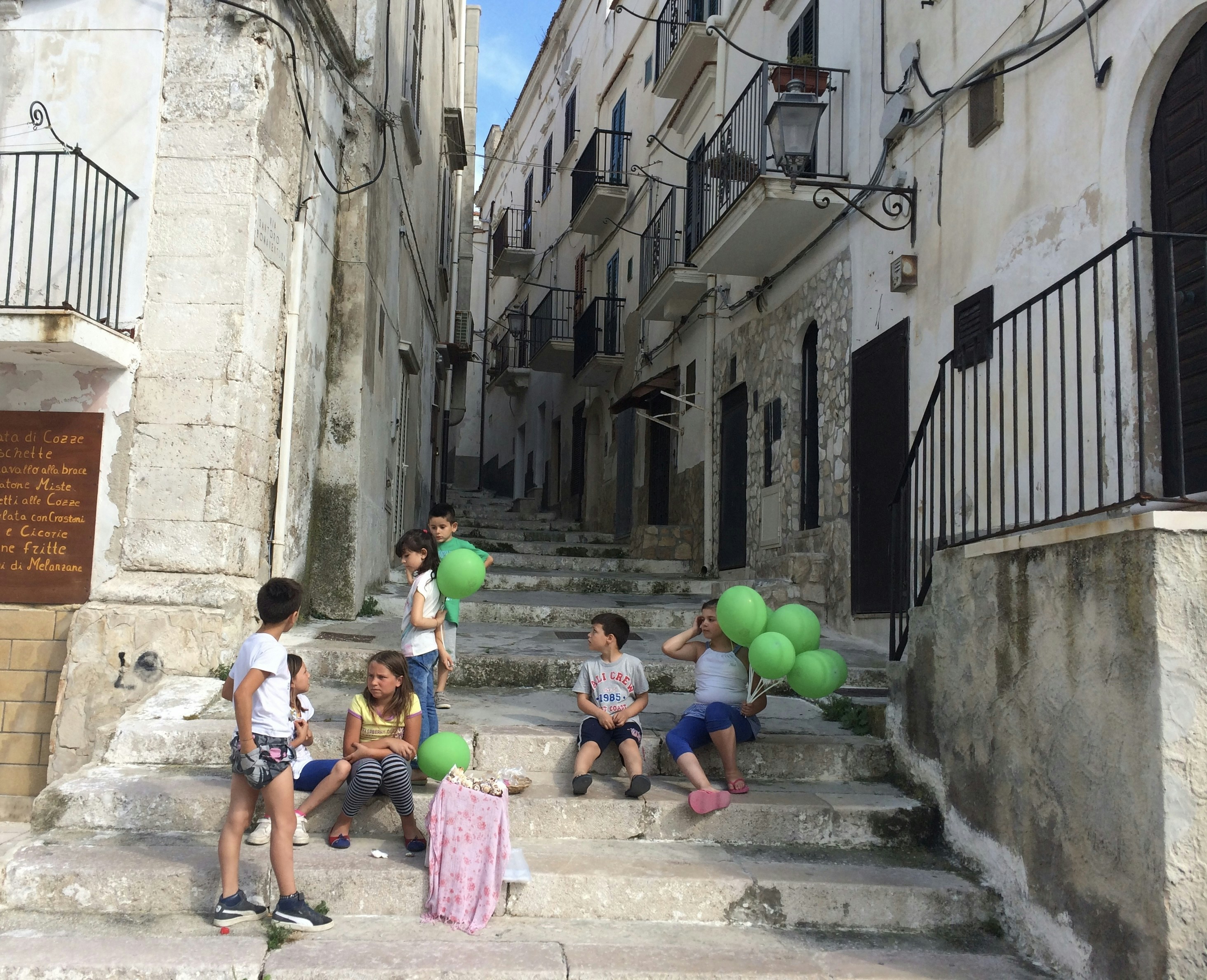 Green Balloons on a Sunlit Staircase in a Mediterranean Alley