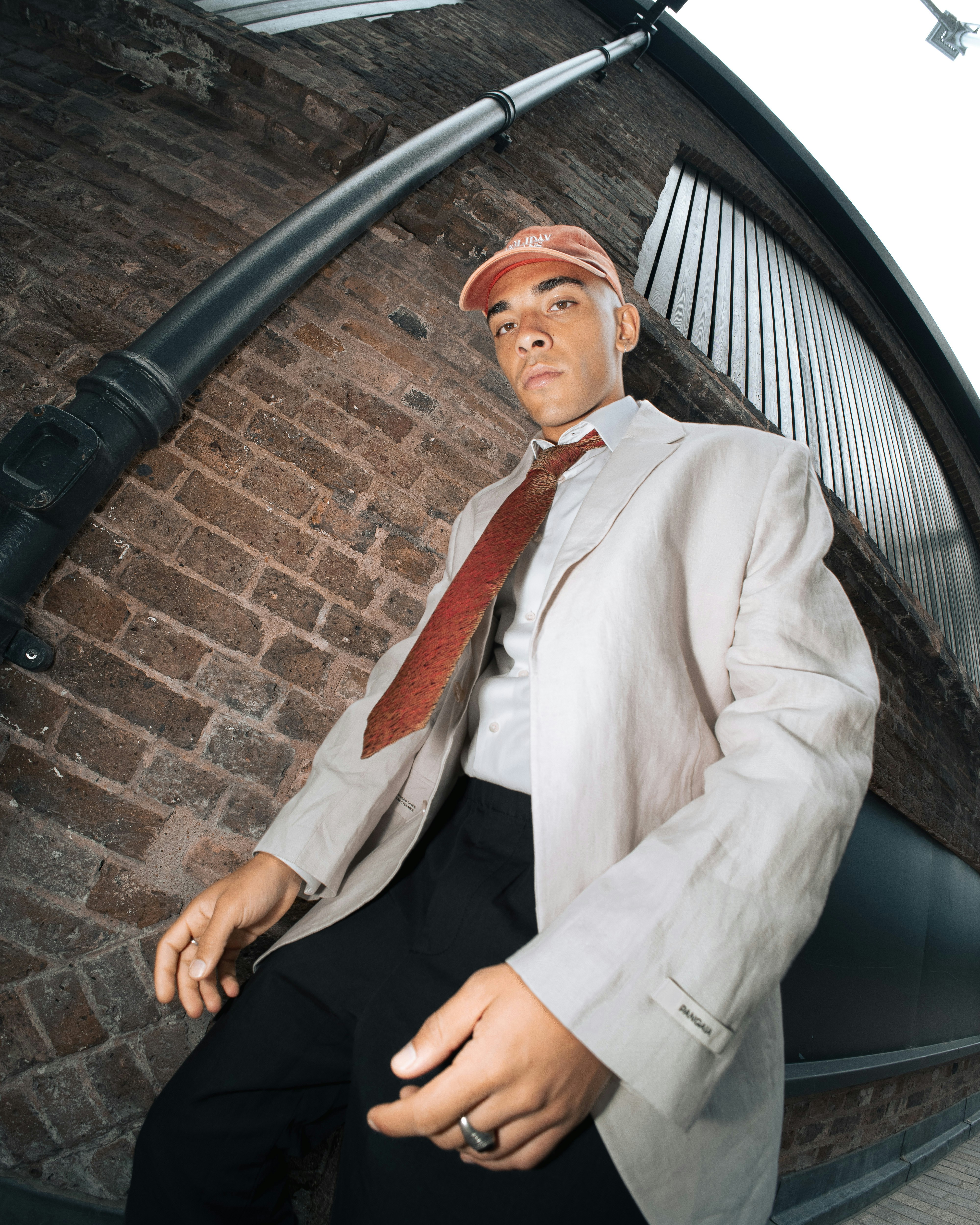 A man in a suit and tie leaning against a brick wall photo – Free ...
