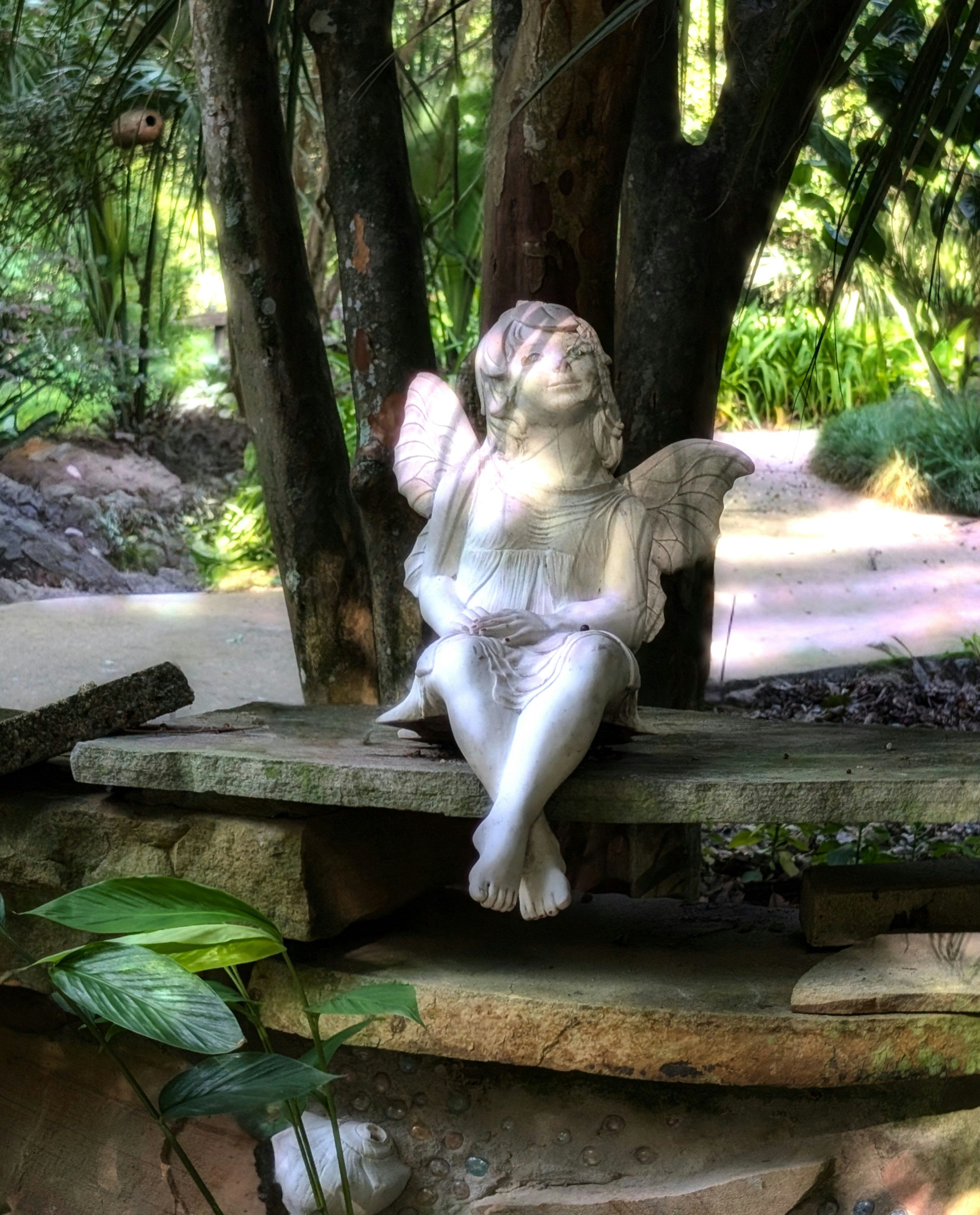 A statue of an angel sitting on a stone bench photo – Free Tree ...