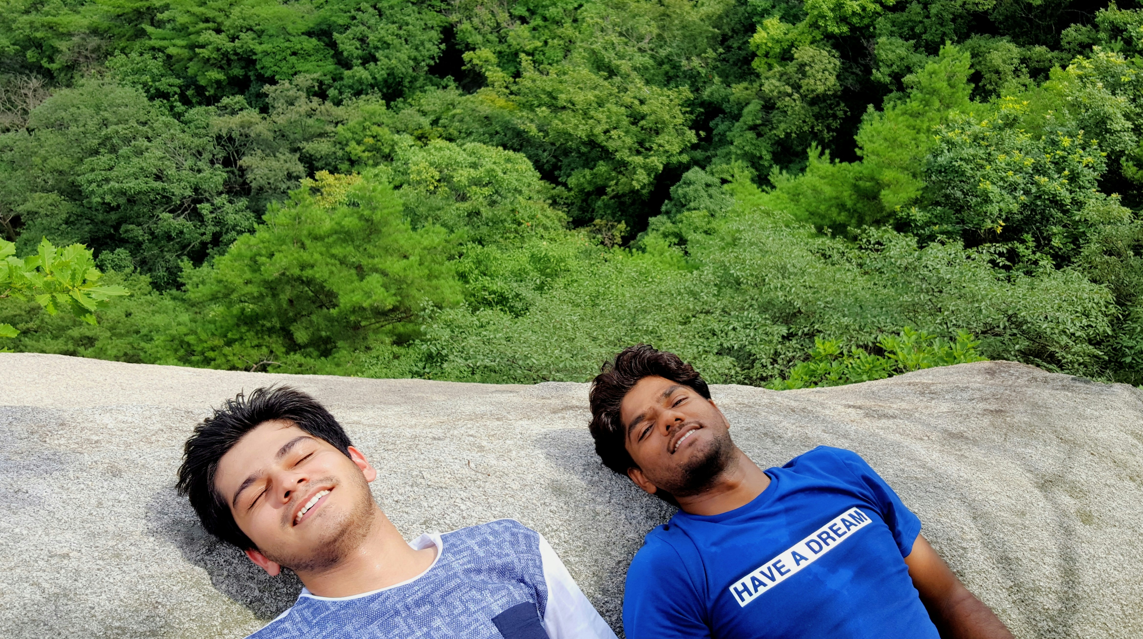 A couple of men laying on top of a large rock photo – Free Rock Image ...