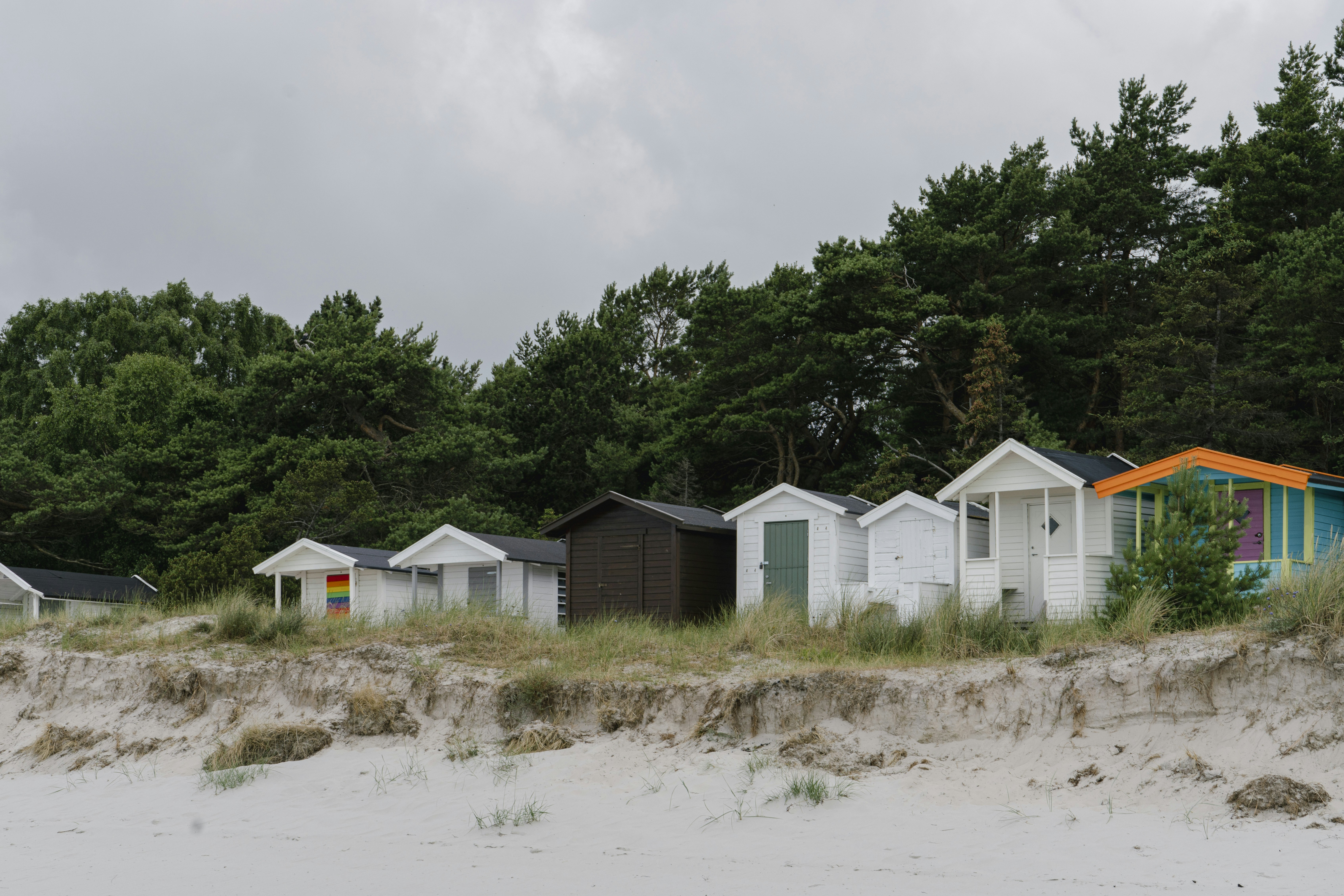 A row of beach huts sitting on top of a sandy beach photo – Free House ...