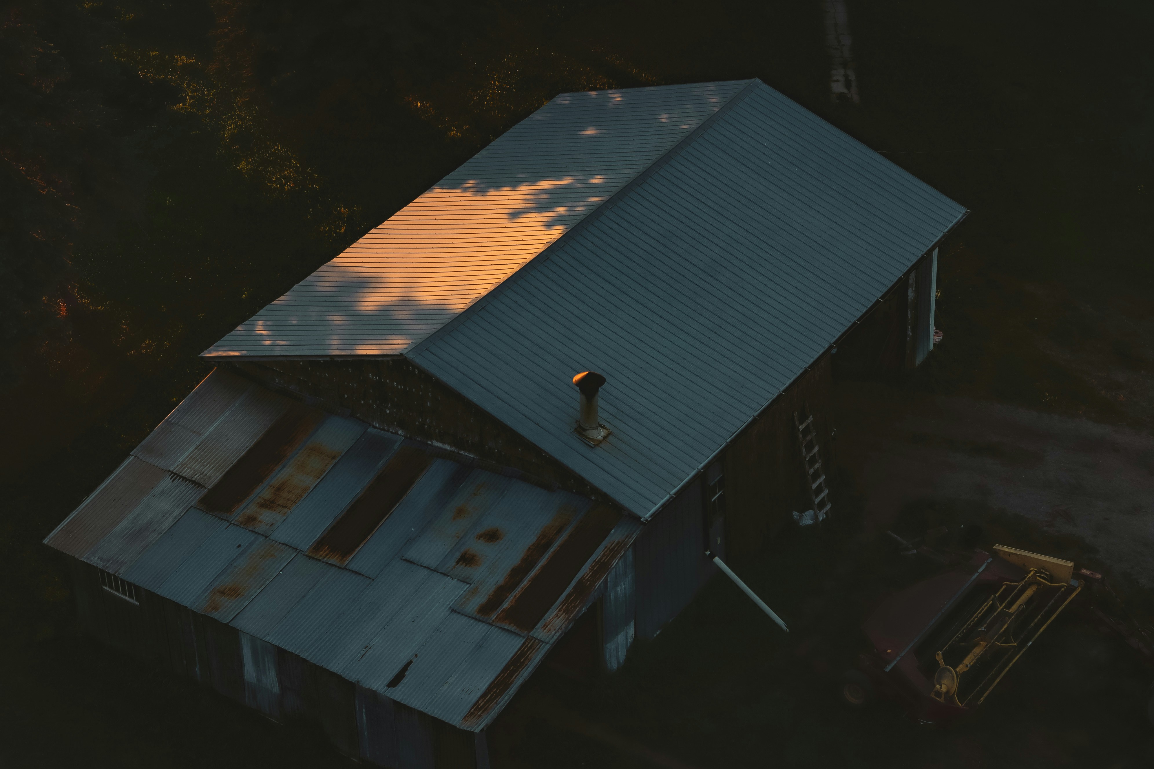 Sunlit Corrugated Roof: Aerial Glimpse of a Rusted Farm Shed at Dusk